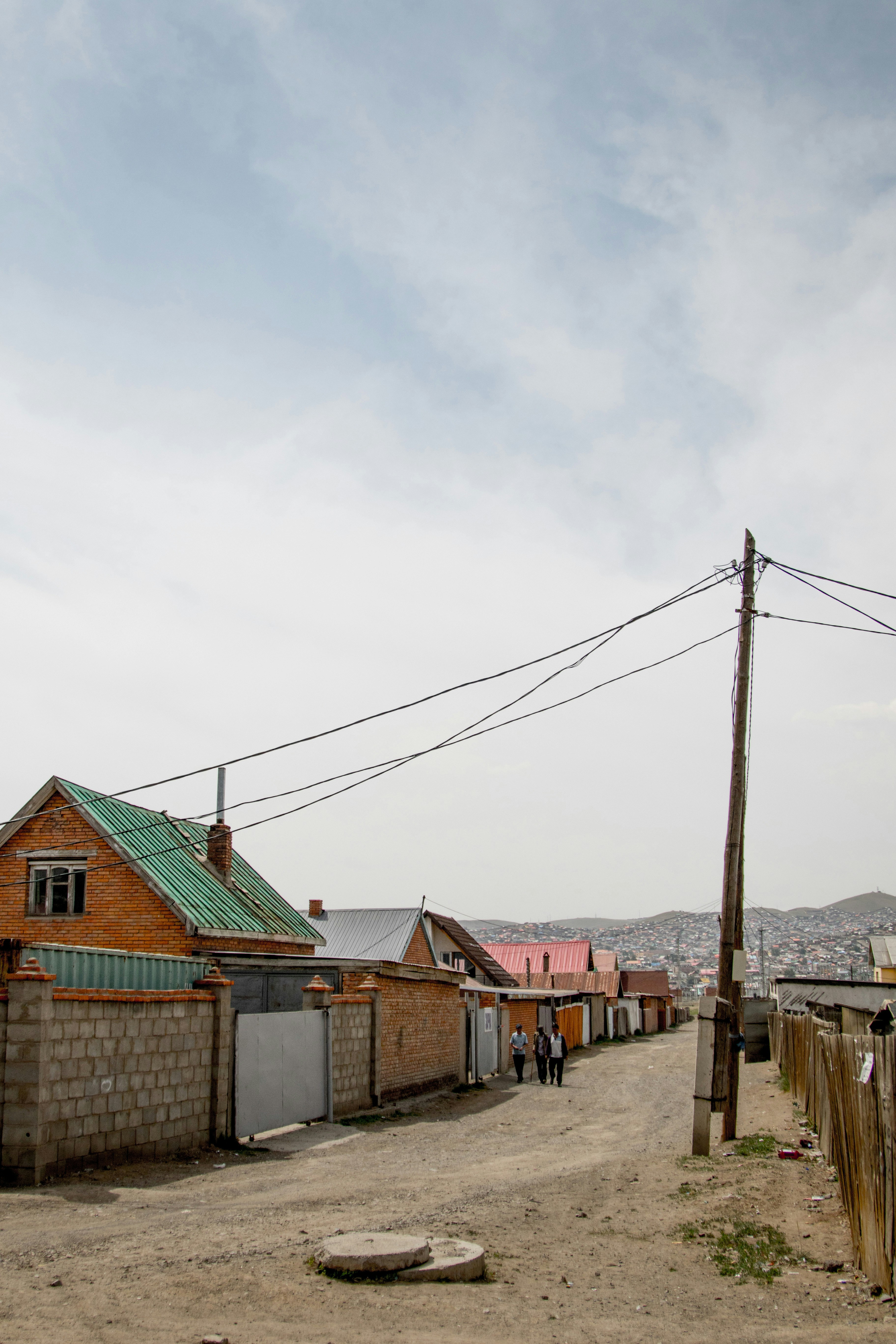 Horizon Walkers: A Dusty Street Flanked by Brick Homes and Power Lines