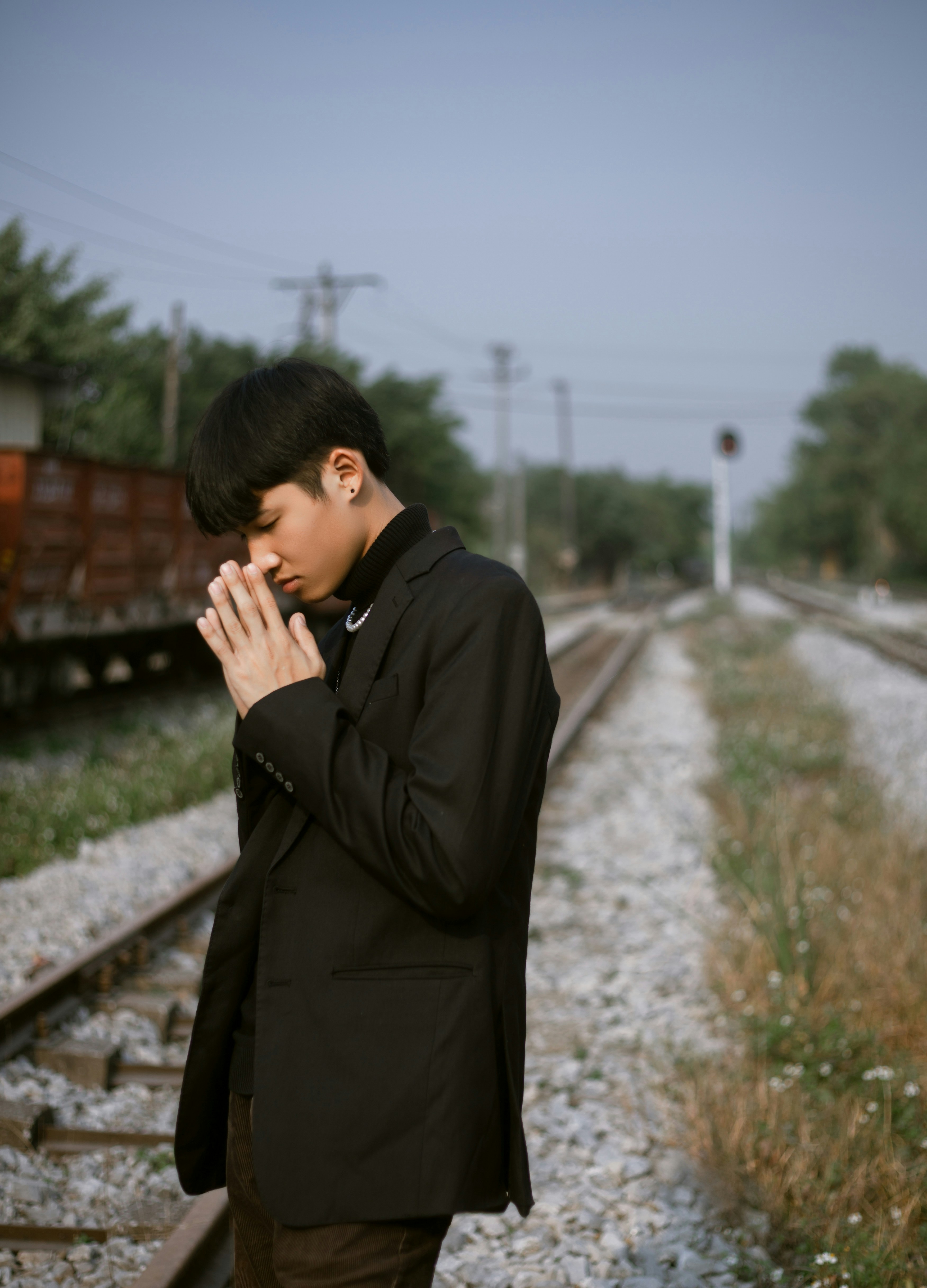 a man standing on a train track with his hands together