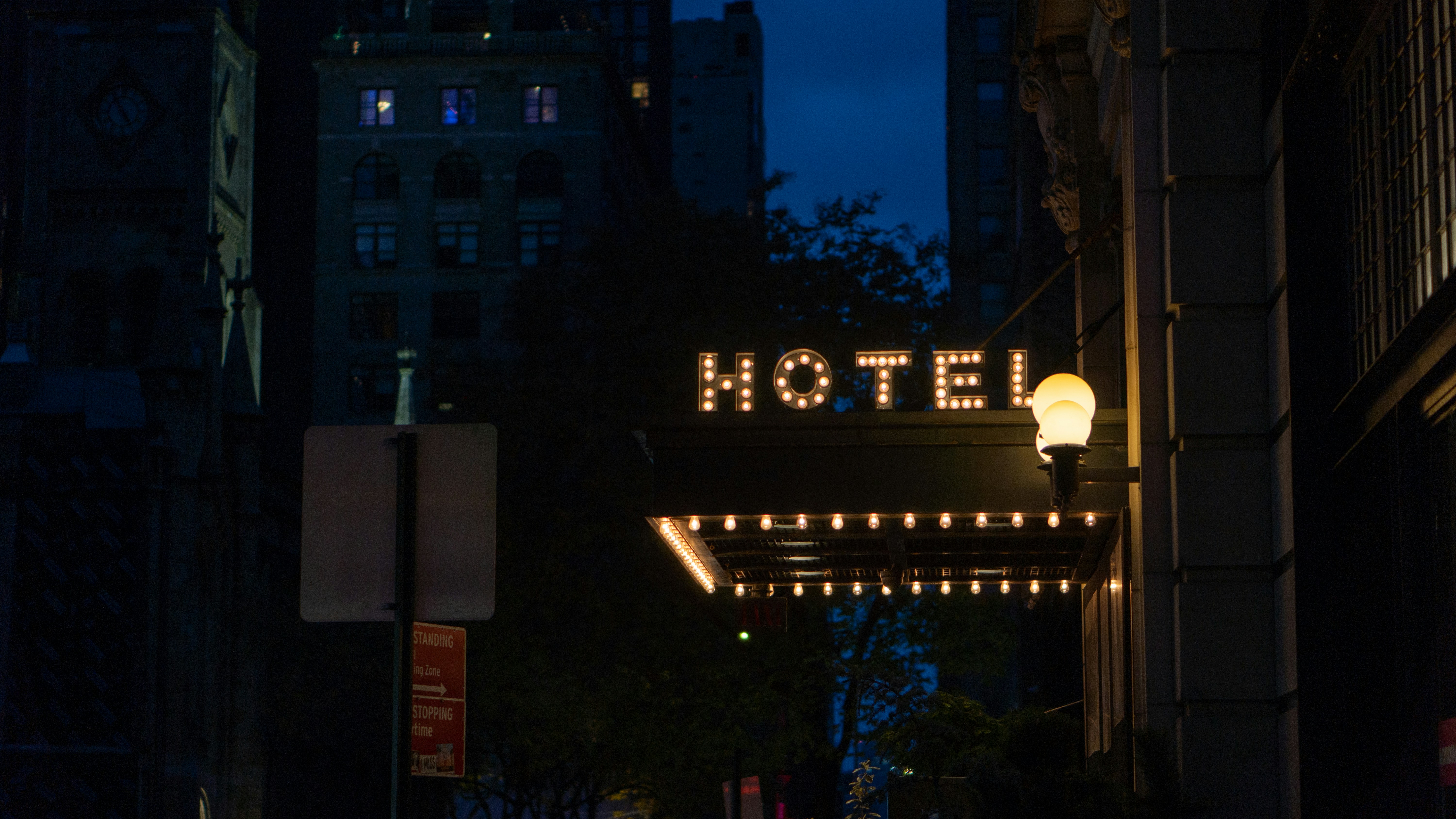 A hotel sign lit up at night on a city street photo – Free New york ...