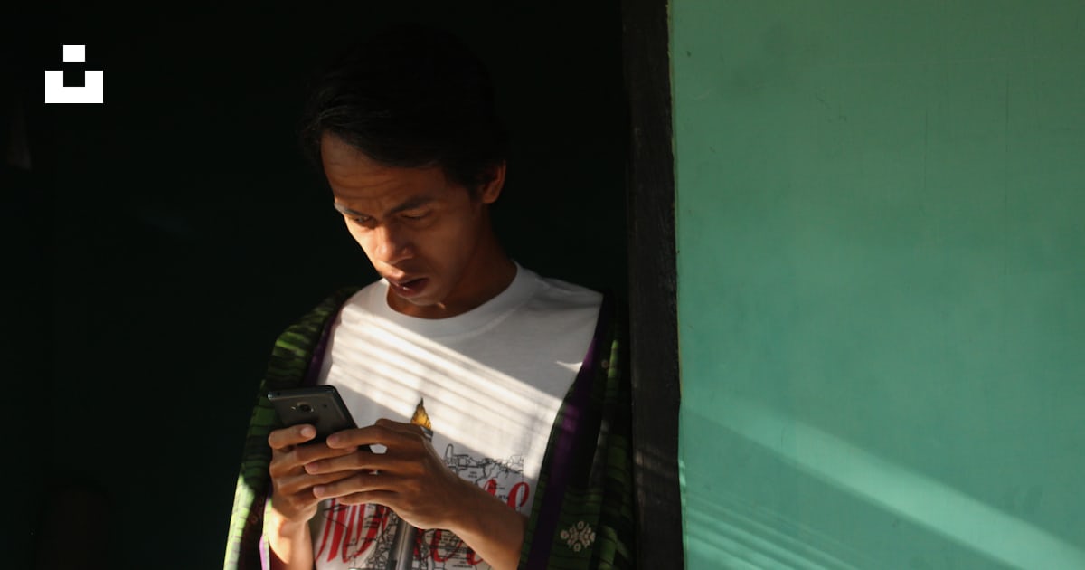 Un Hombre Mirando Su Teléfono Celular En Una Puerta Foto Imagen De