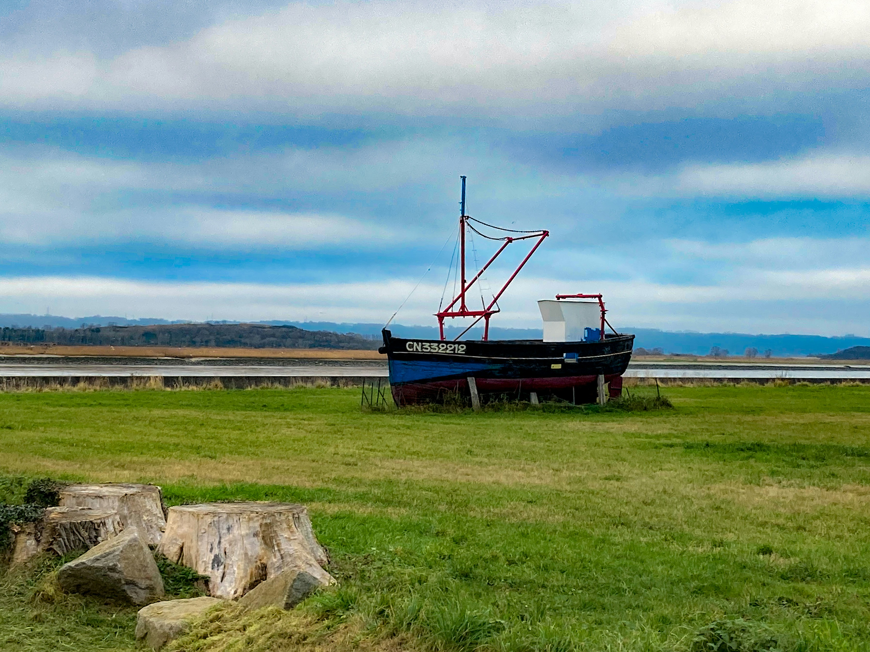 Blue Boat on a Quiet Coastal Grassland Under a Wide, Cloud-Swept Sky