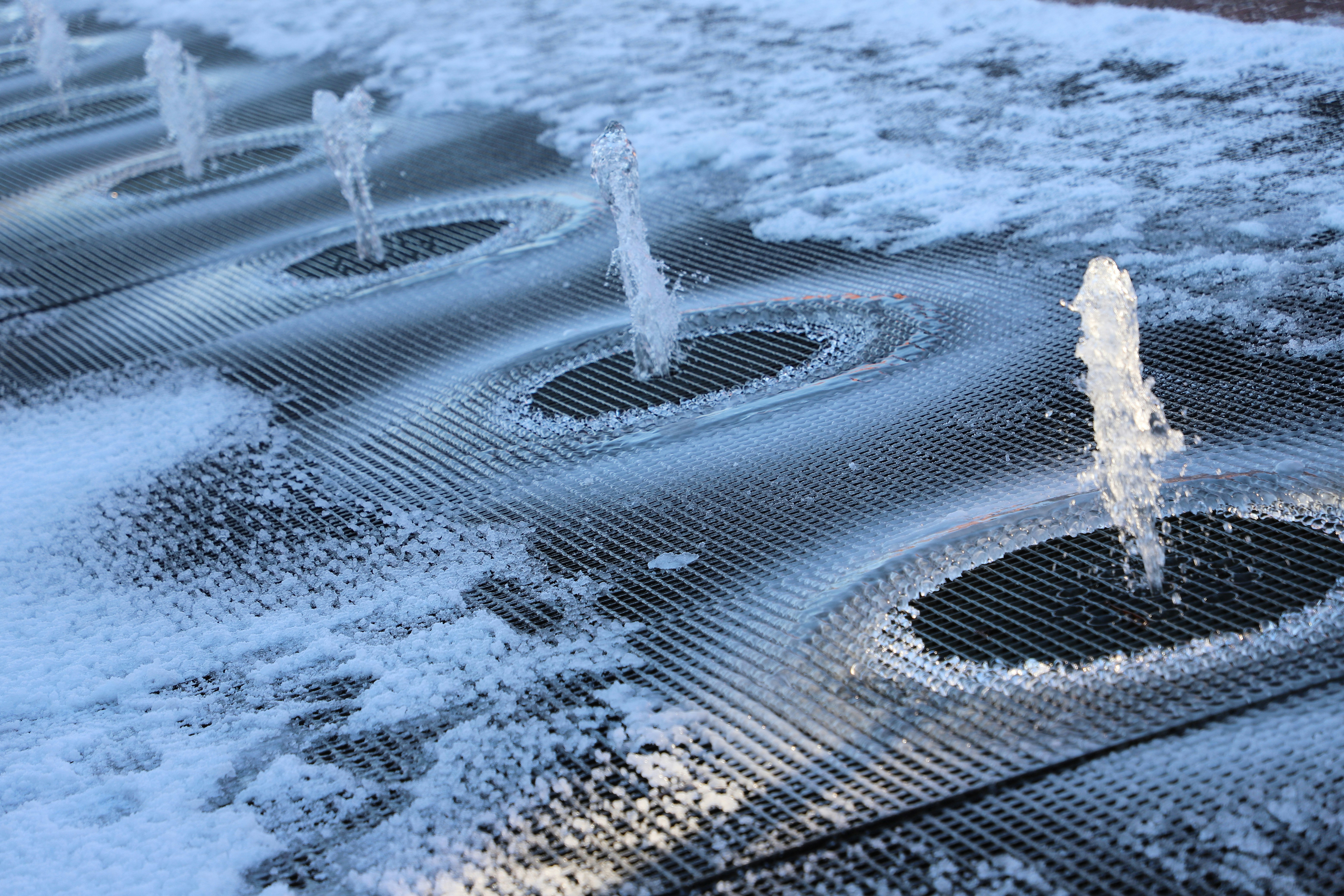 A row of water spouting out of a drain in the snow photo – Free ...