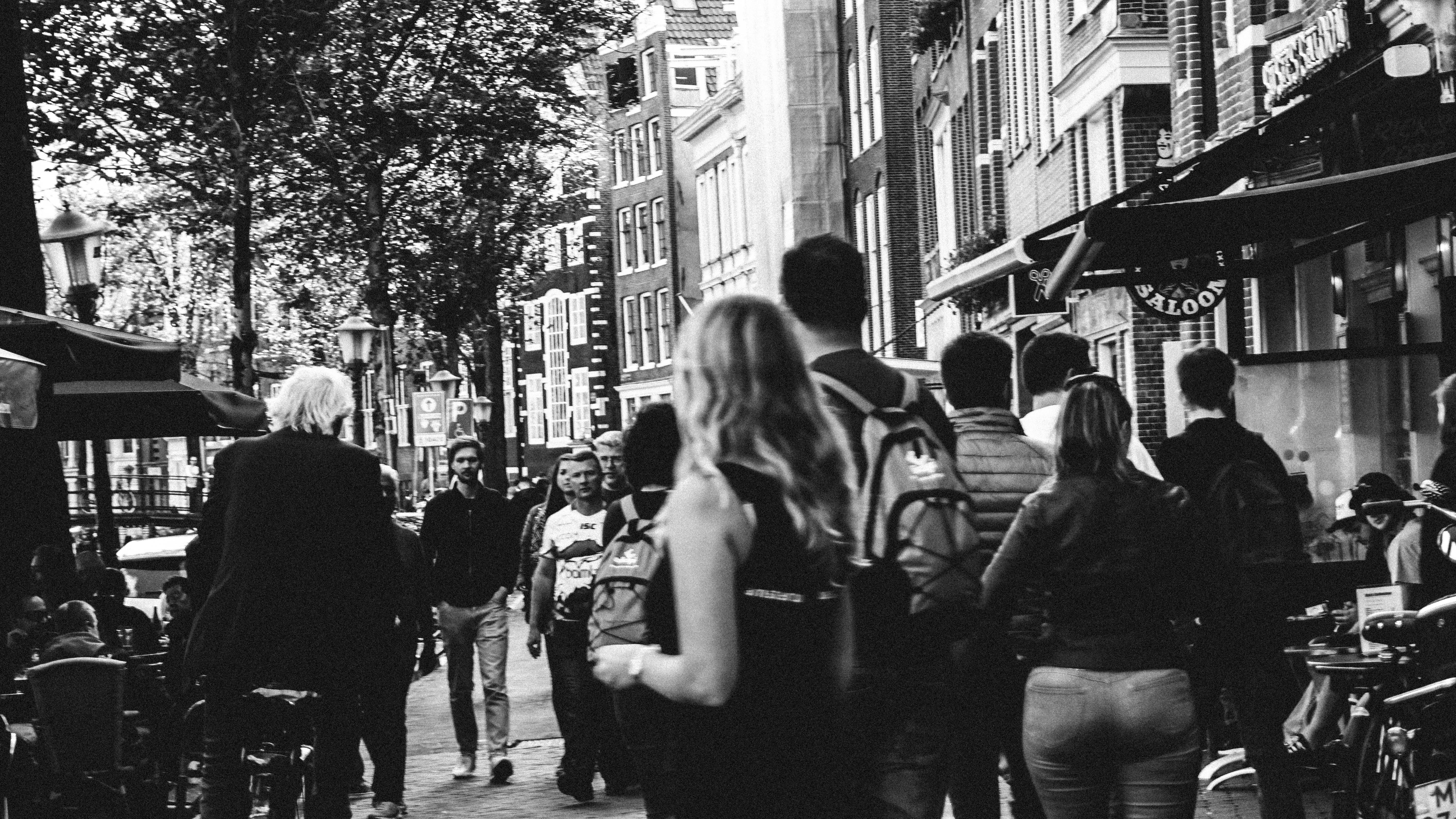 Eine Gruppe von Menschen, die eine Straße neben hohen Gebäuden entlang ...