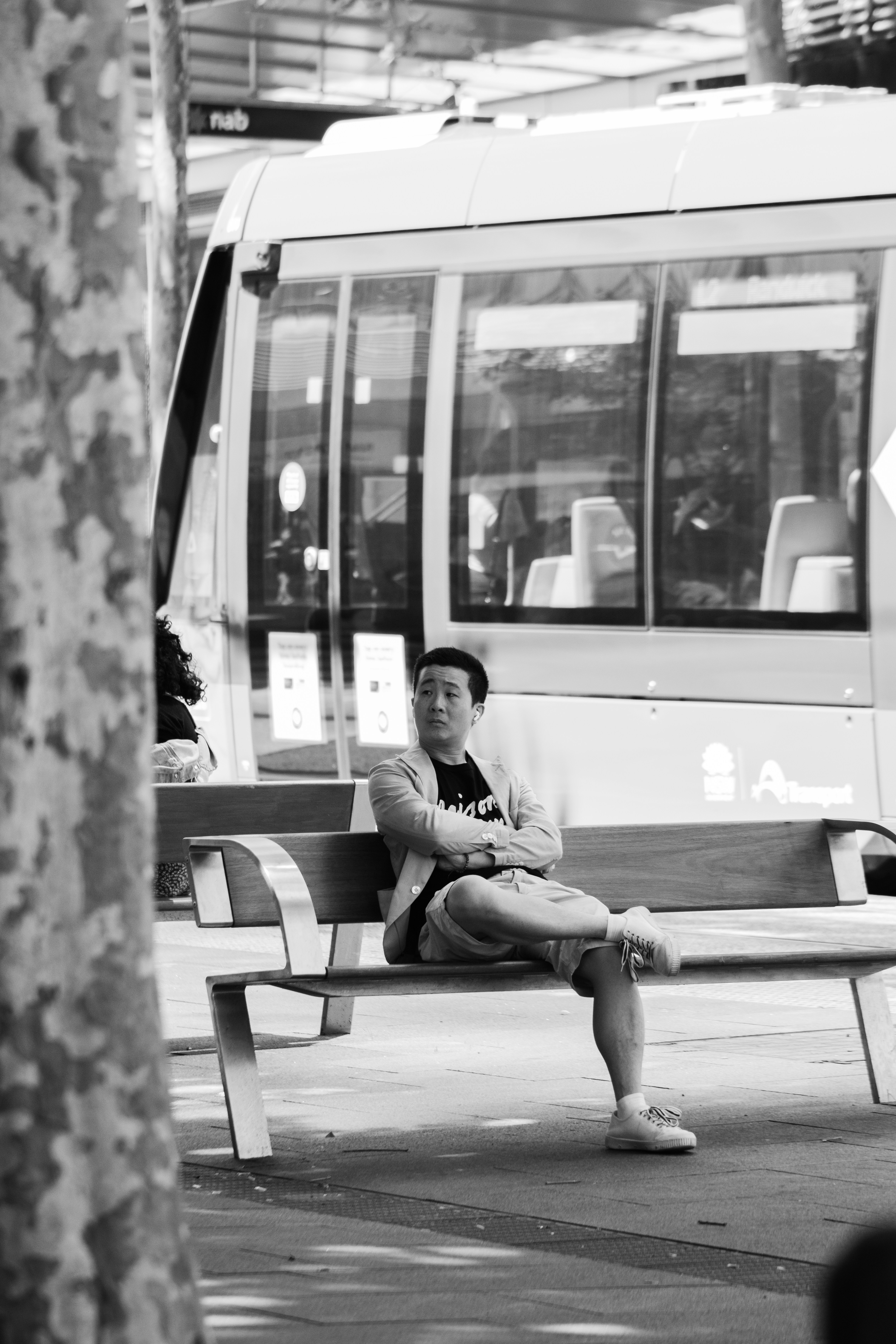 a man sitting on a bench in front of a bus