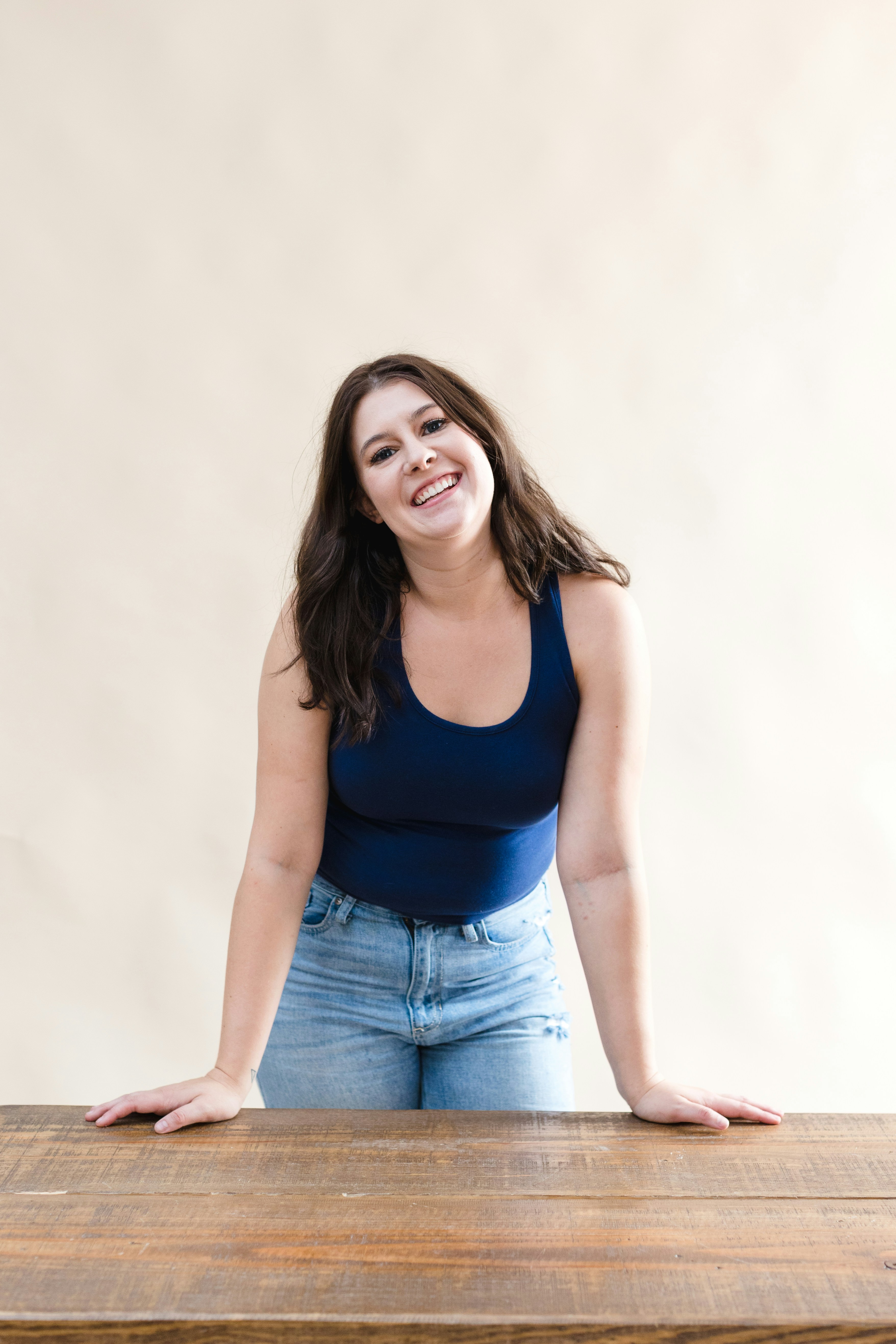 A woman in a blue tank top leaning on a wooden table photo – Free Usa ...