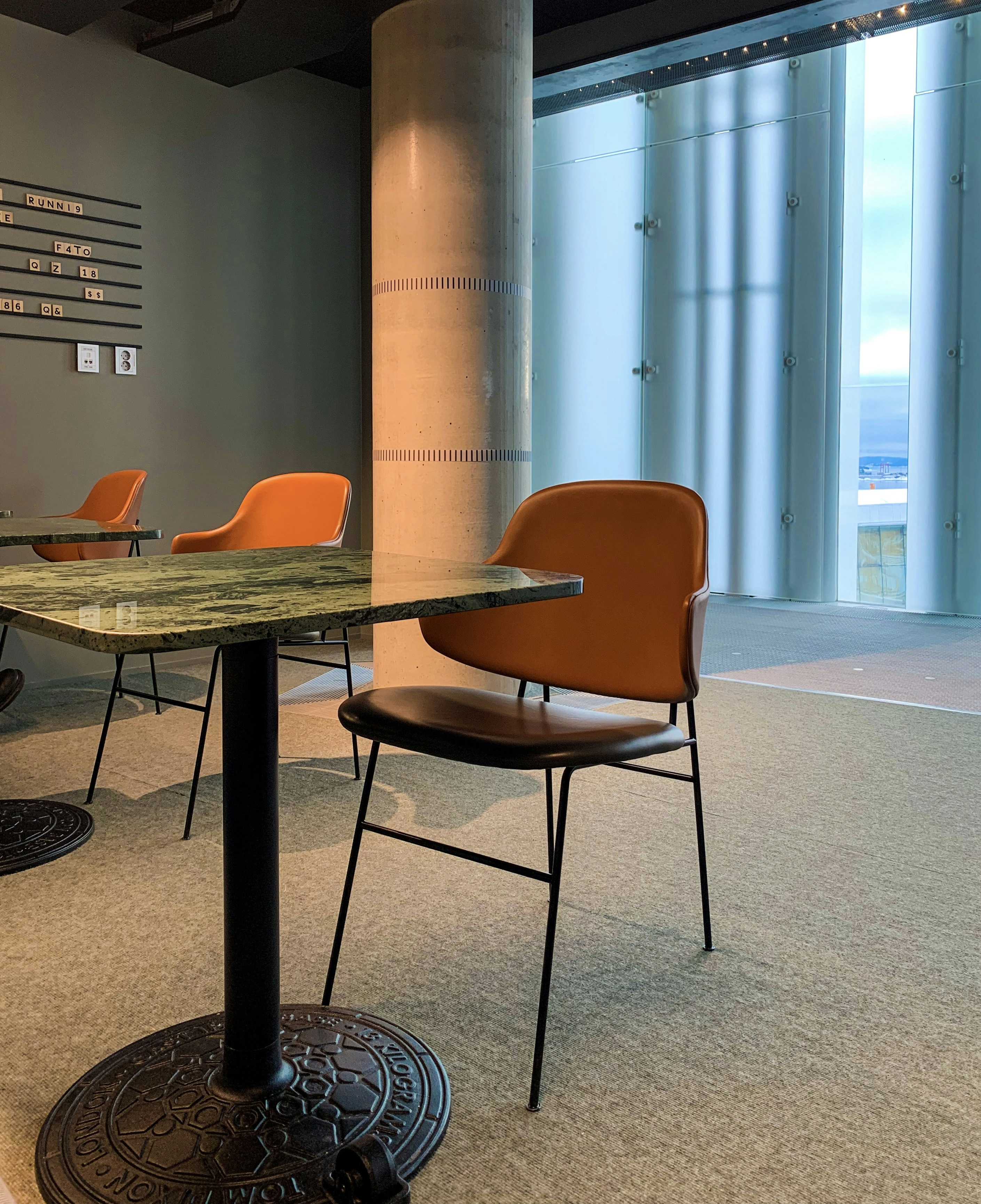 Orange Accent Chairs Anchor a Quiet Glass-Walled Lounge
