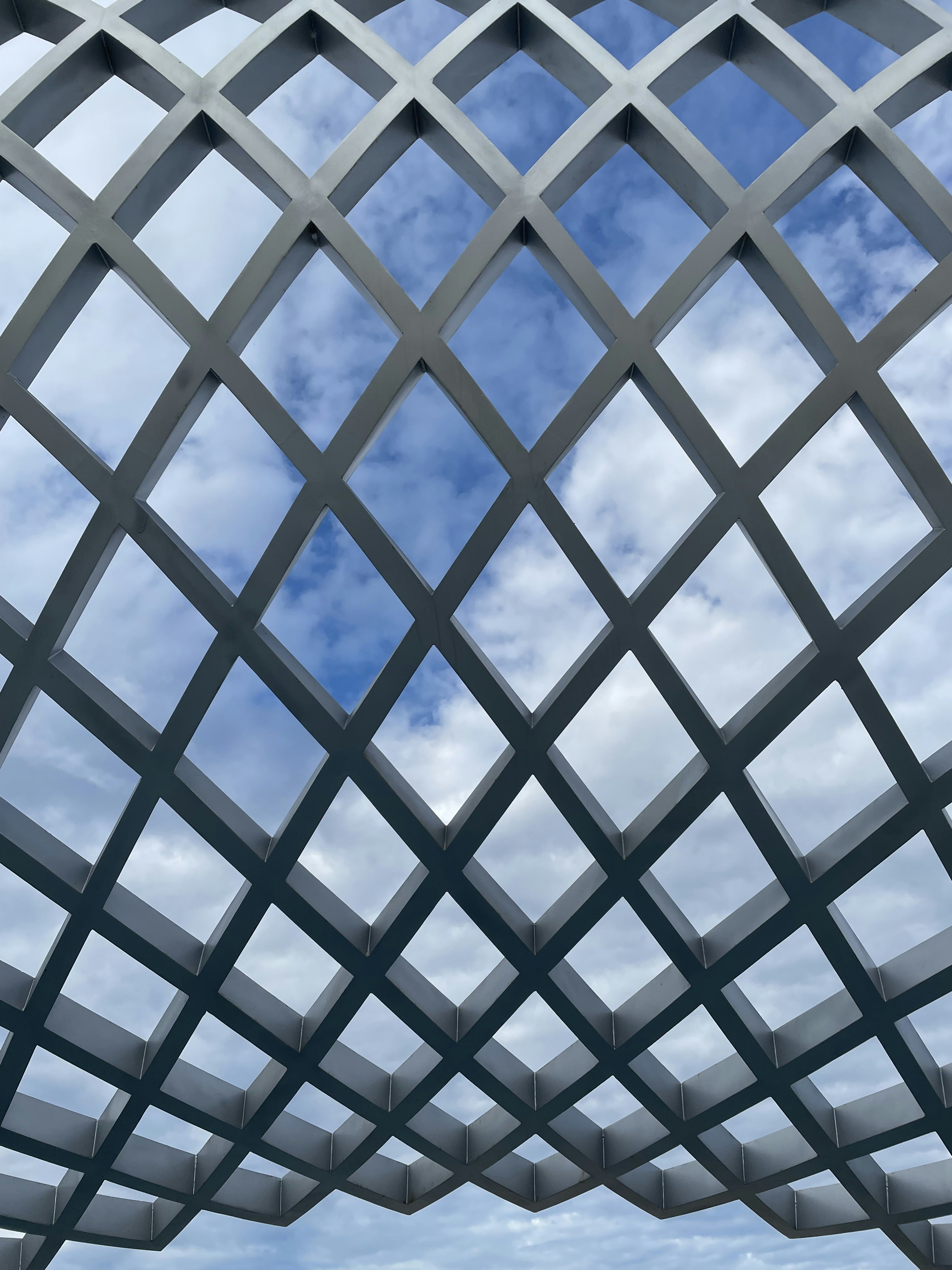 Intricate lattice structure framing a serene sky filled with soft clouds.