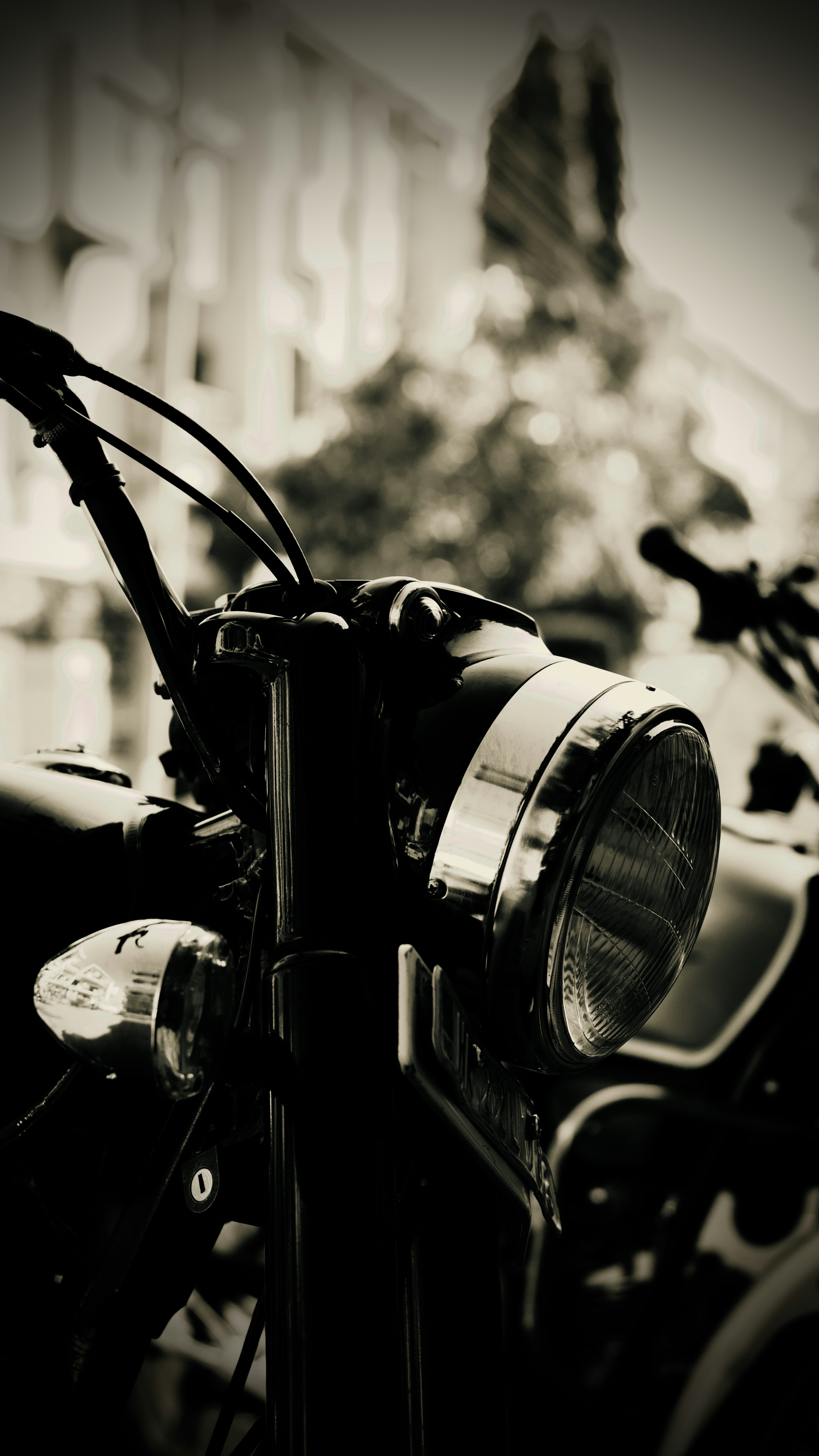 Close-up of a classic motorcycle's headlight and handlebars, showcasing intricate details and vintage charm.