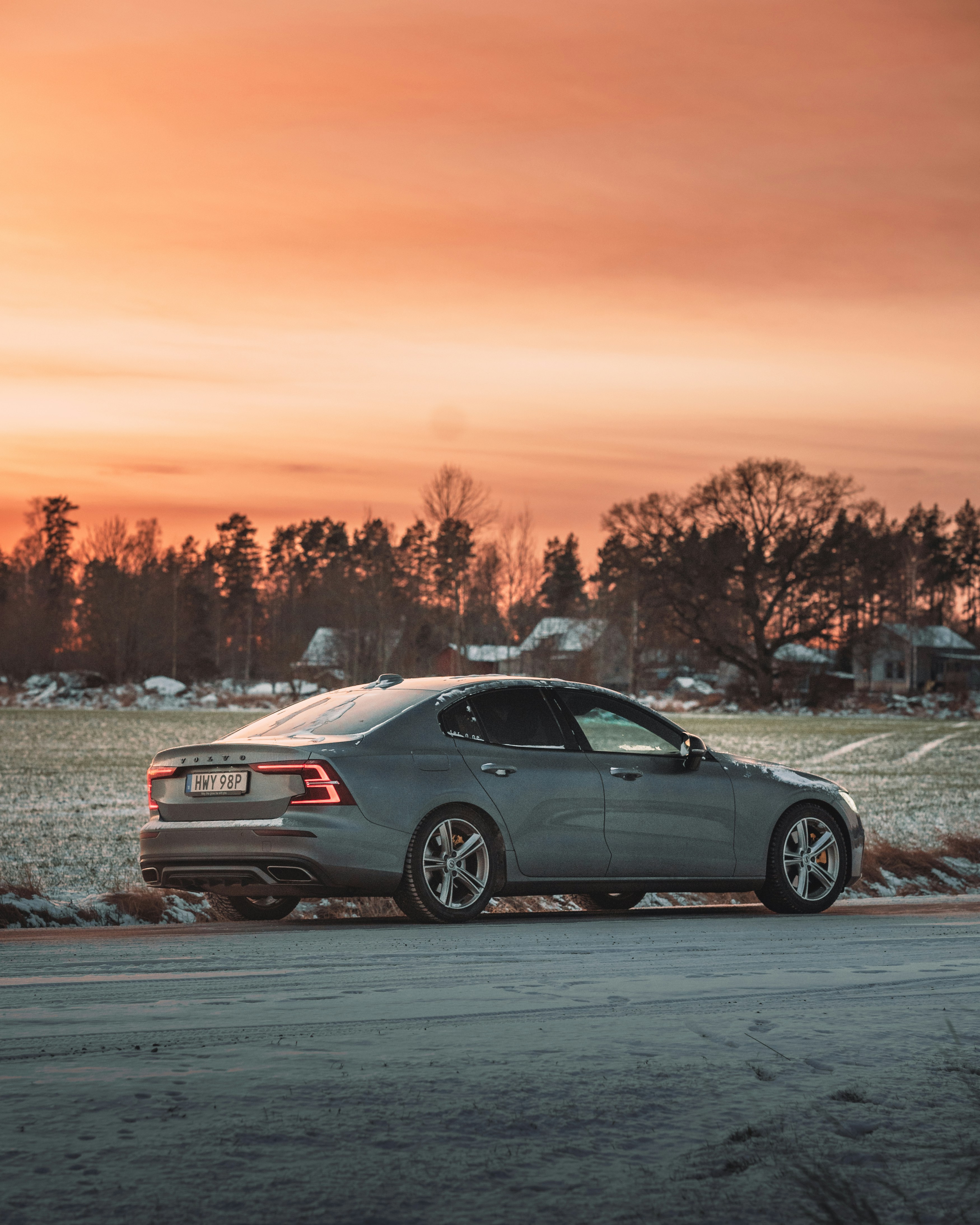 Dusk Drive: Silver Sedan on Frosted Roads Under a Molten Sunset