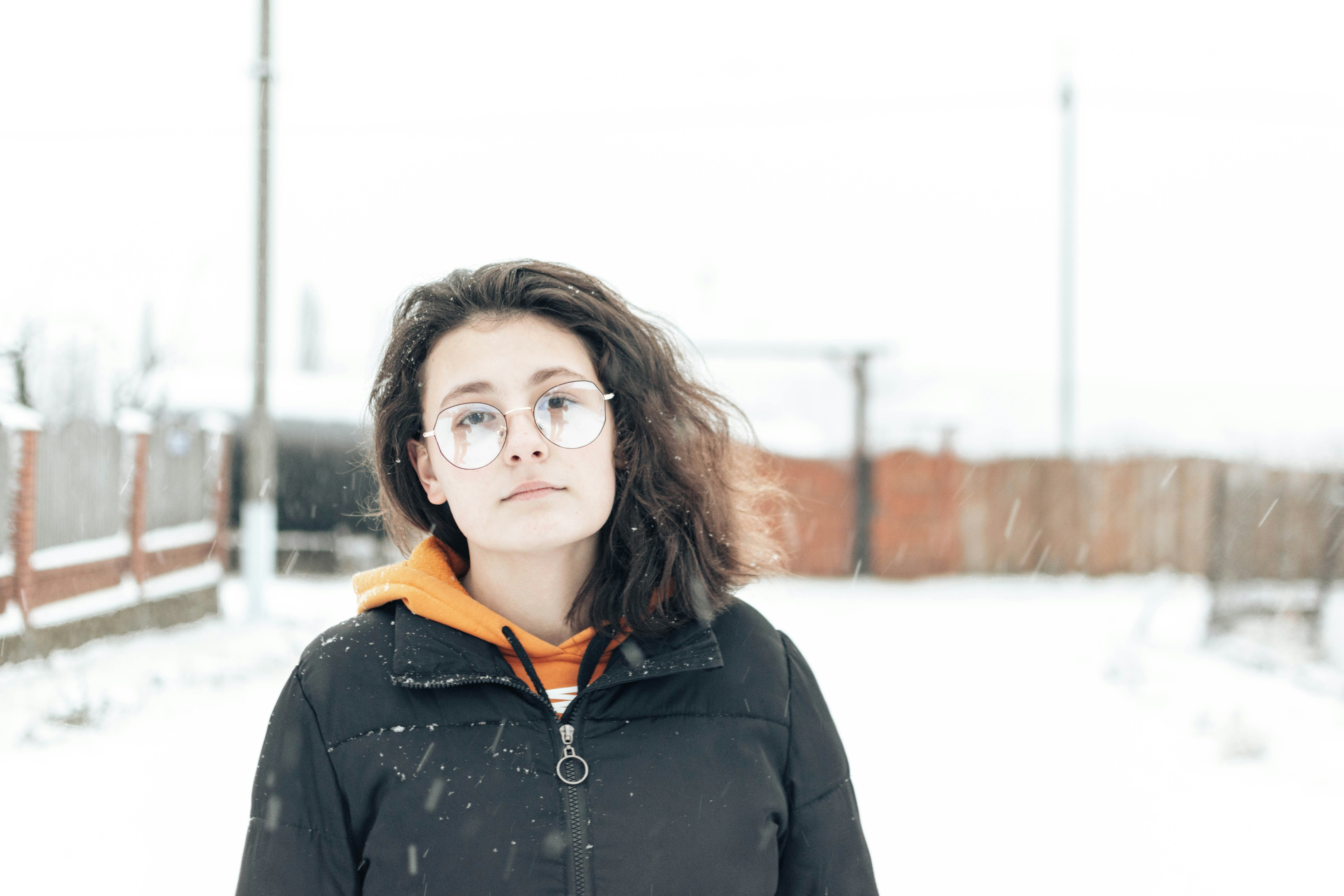 a woman wearing glasses standing in the snow