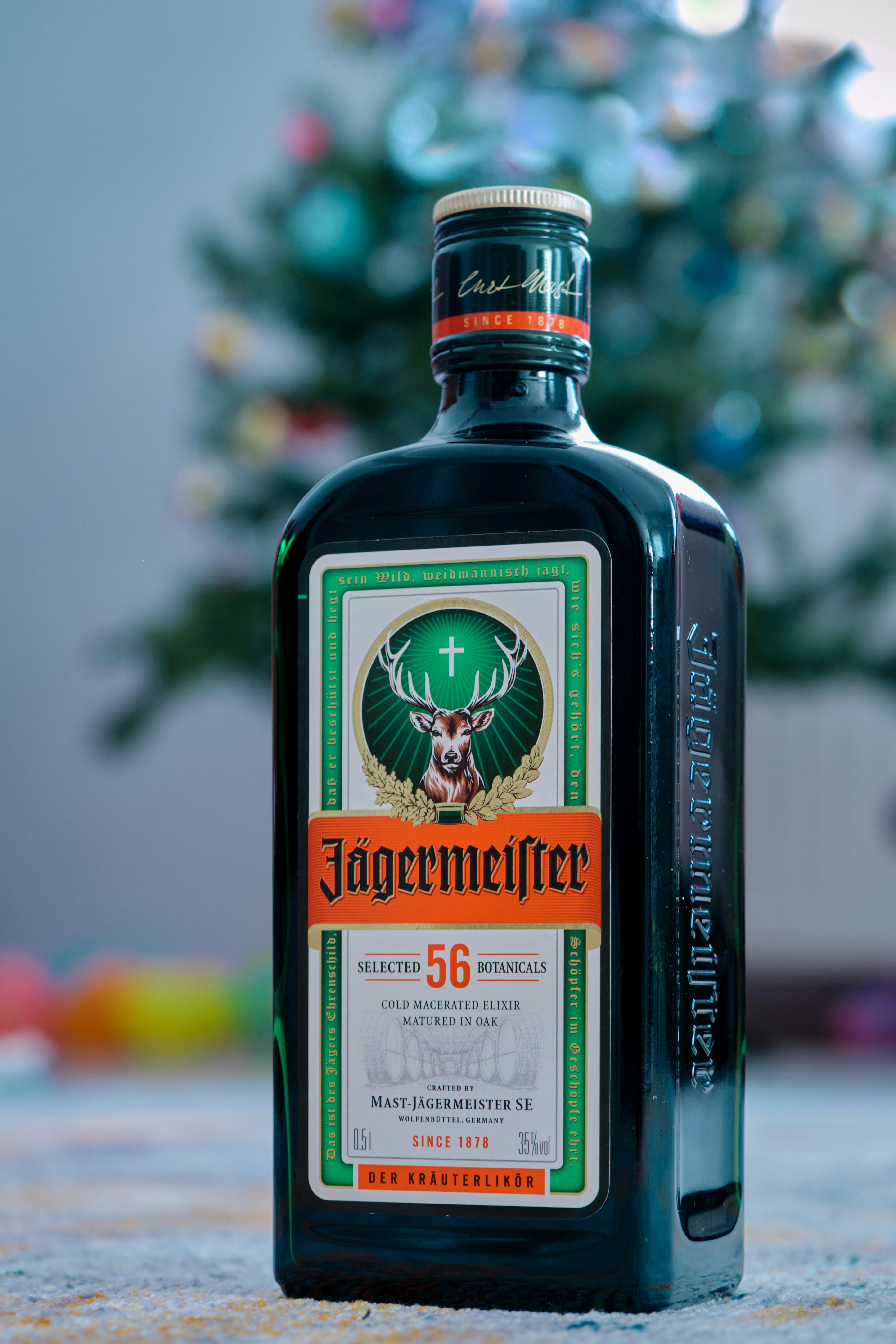 A bottle of liquor sitting on a table next to a christmas tree photo ...