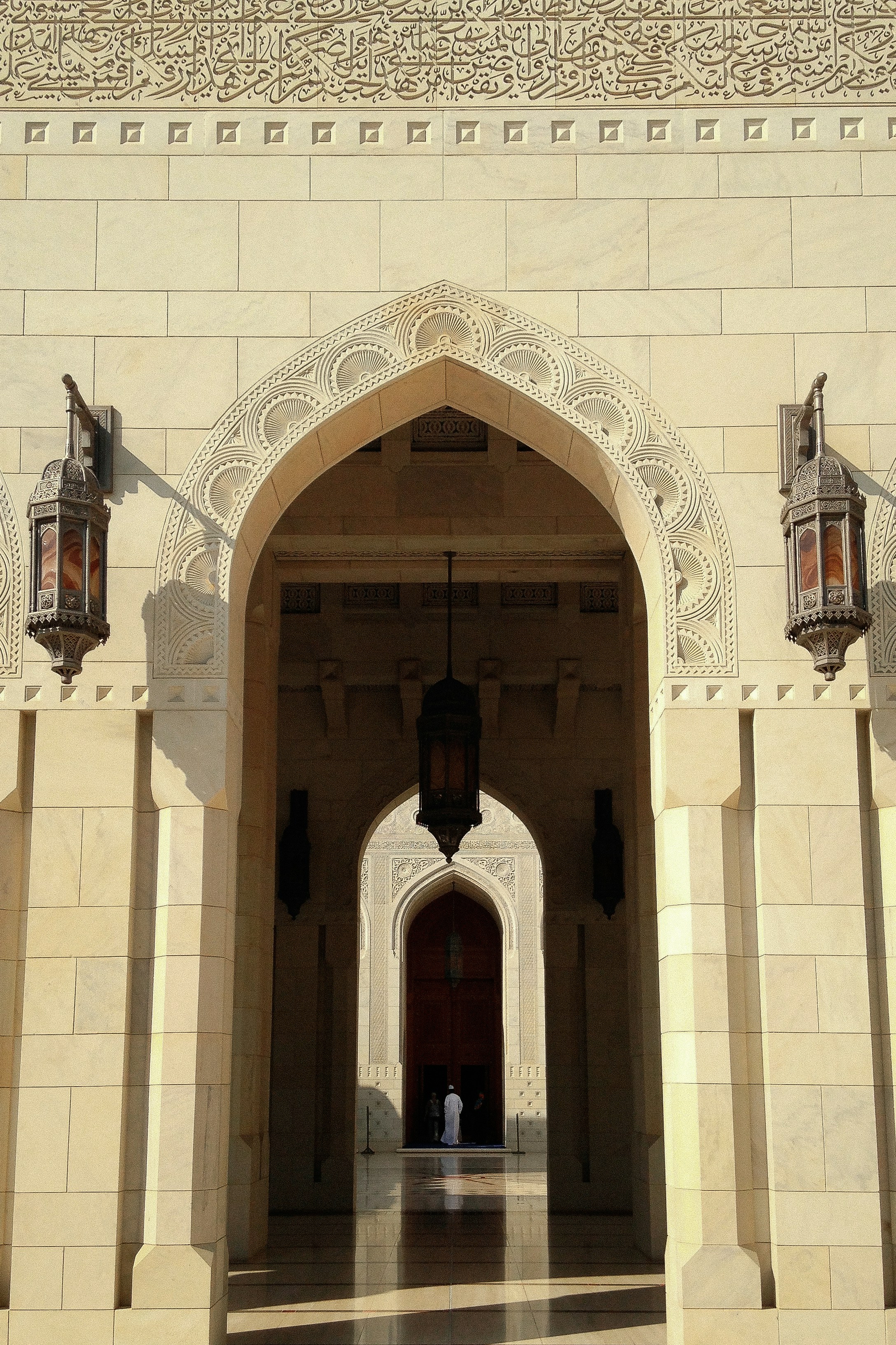 Intricate architectural arches adorned with ornate carvings and lanterns, leading to a grand entrance. The scene captures the essence of traditional design and cultural heritage.