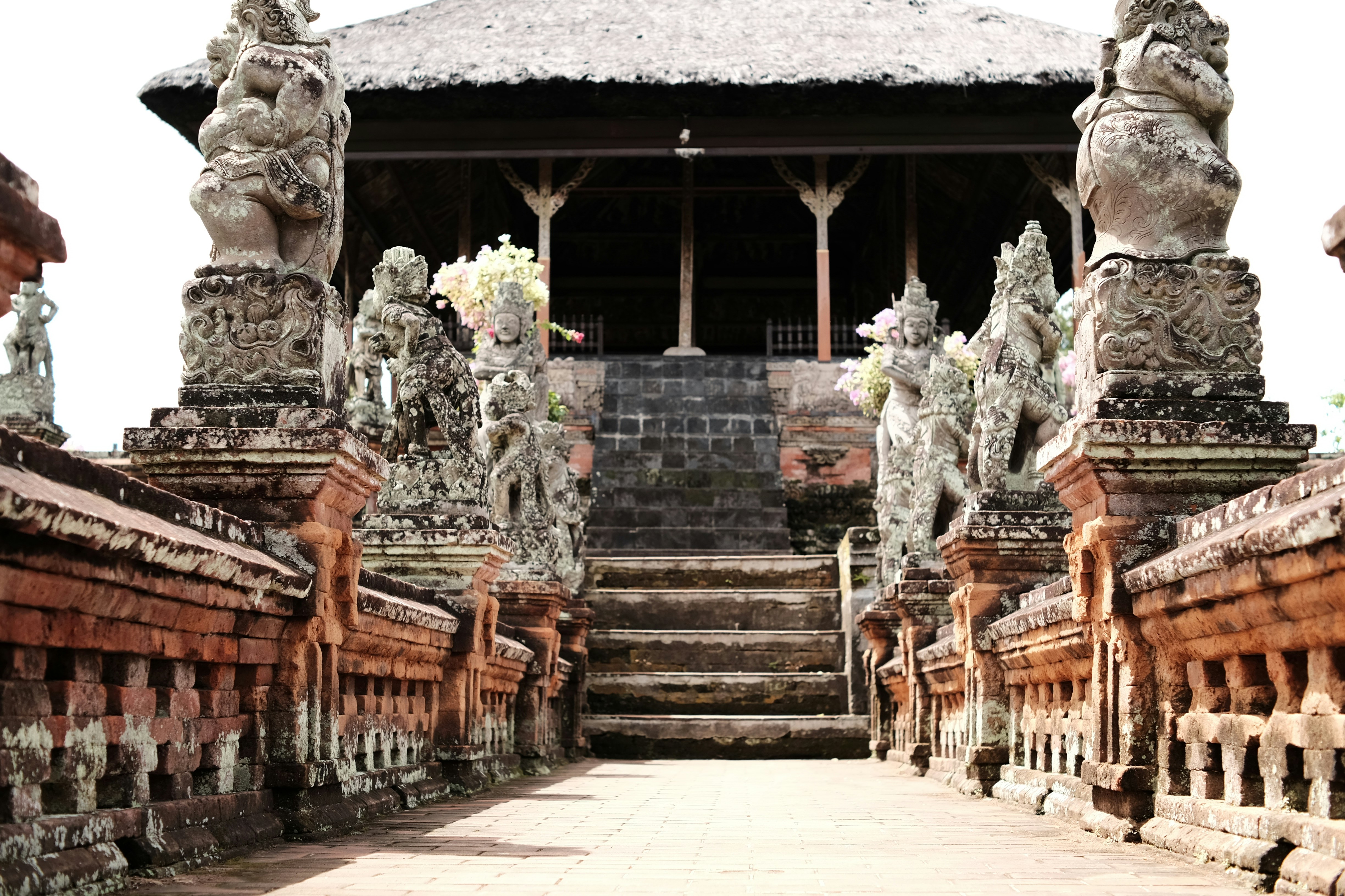 Intricate stone carvings line the pathway leading to a traditional Balinese temple, showcasing cultural artistry and architectural beauty.