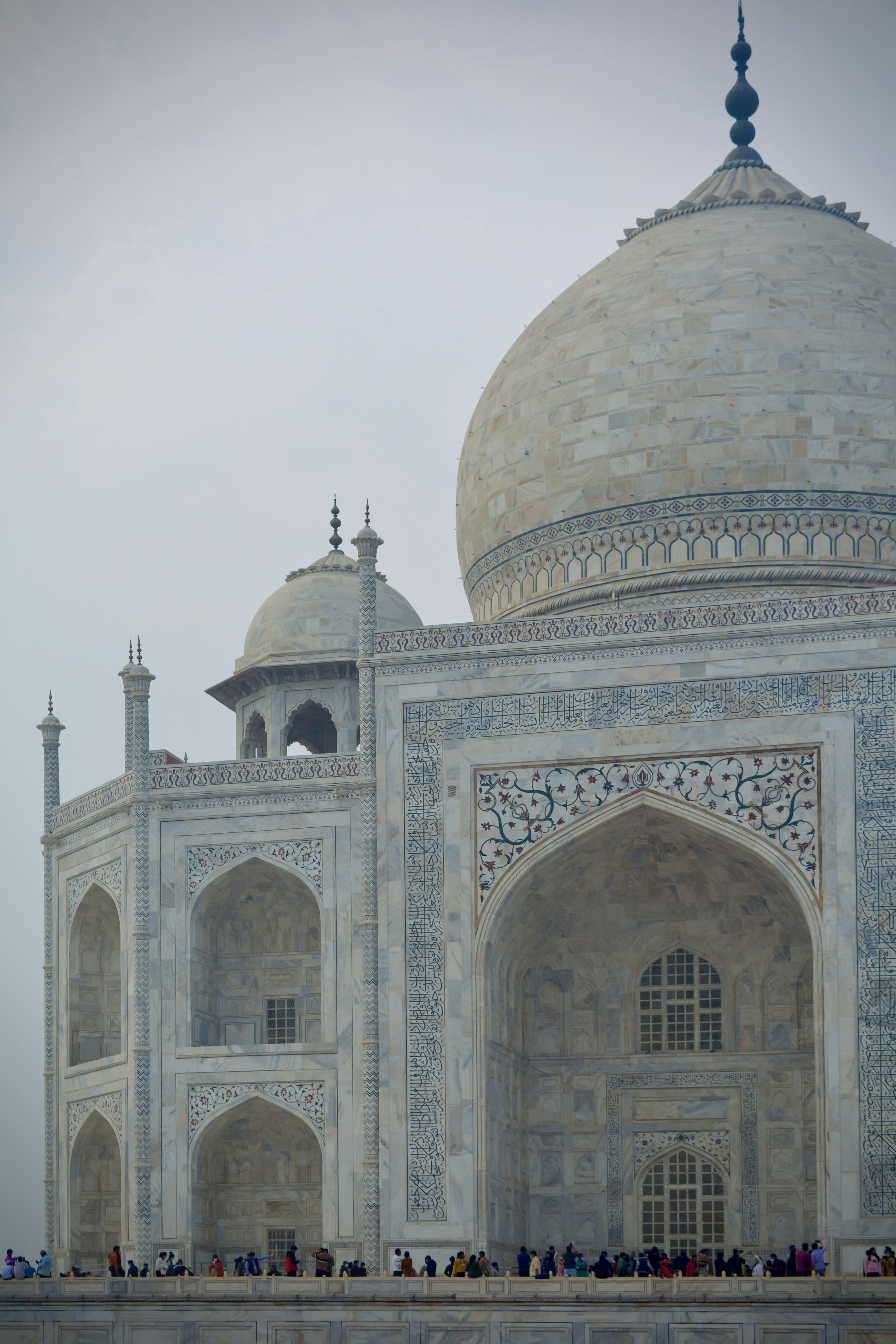 Close-up view of the Taj Mahal's ornate architecture, showcasing intricate designs and visitors admiring its beauty.