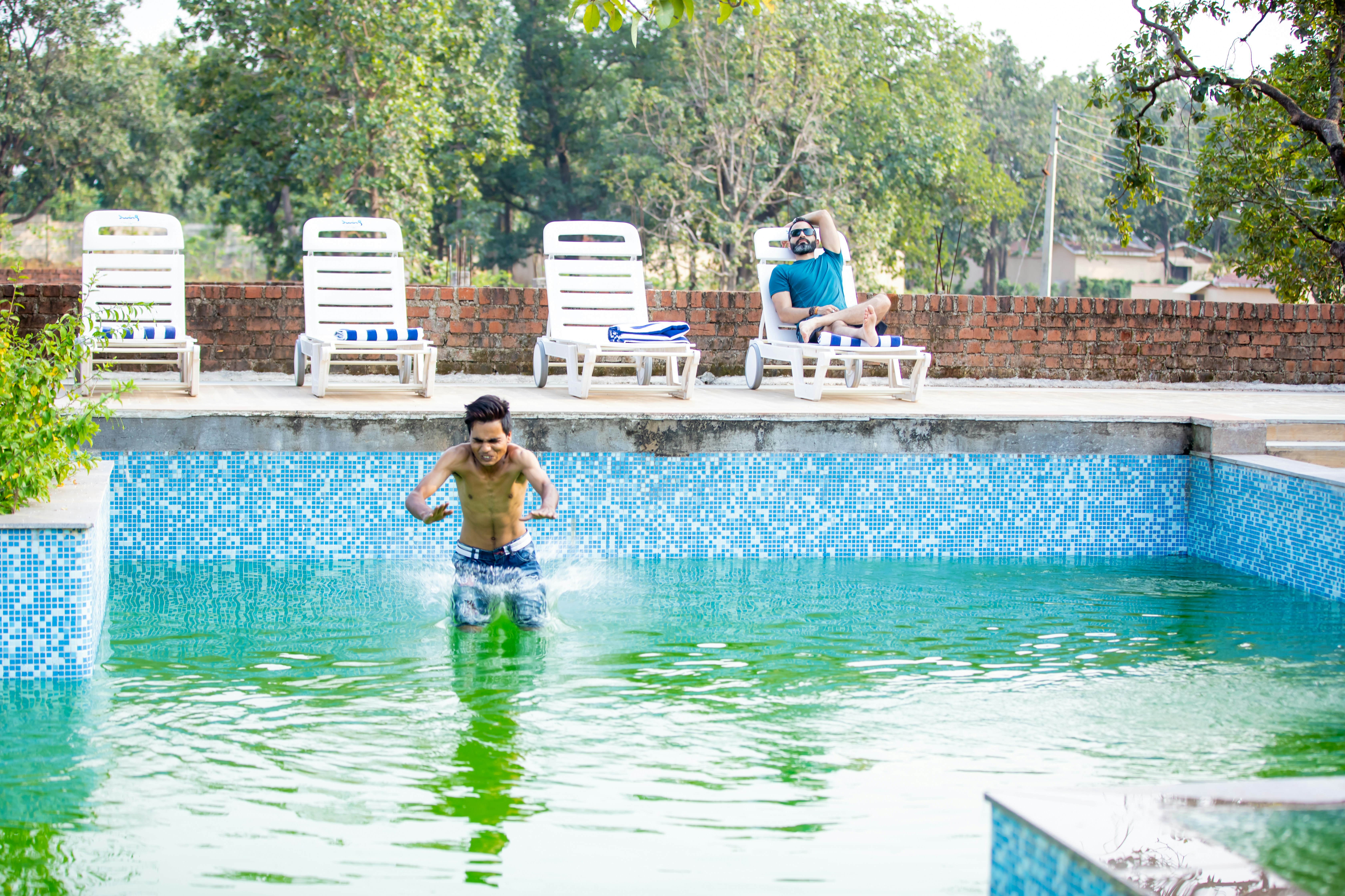 A man standing in a swimming pool surrounded by lawn chairs photo ...