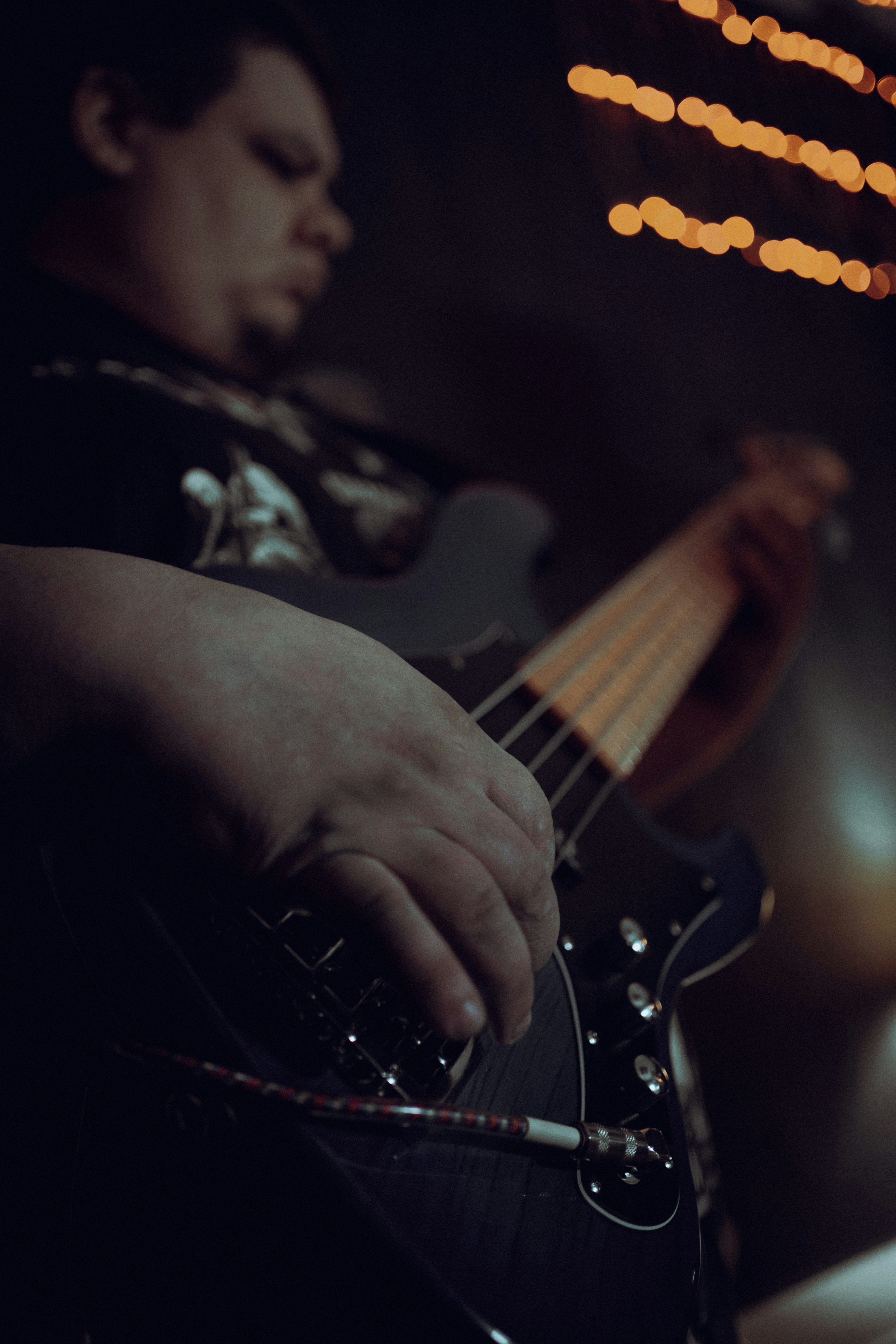 Dim Stage Focus: Hands Crafting a Bassline in Low Light