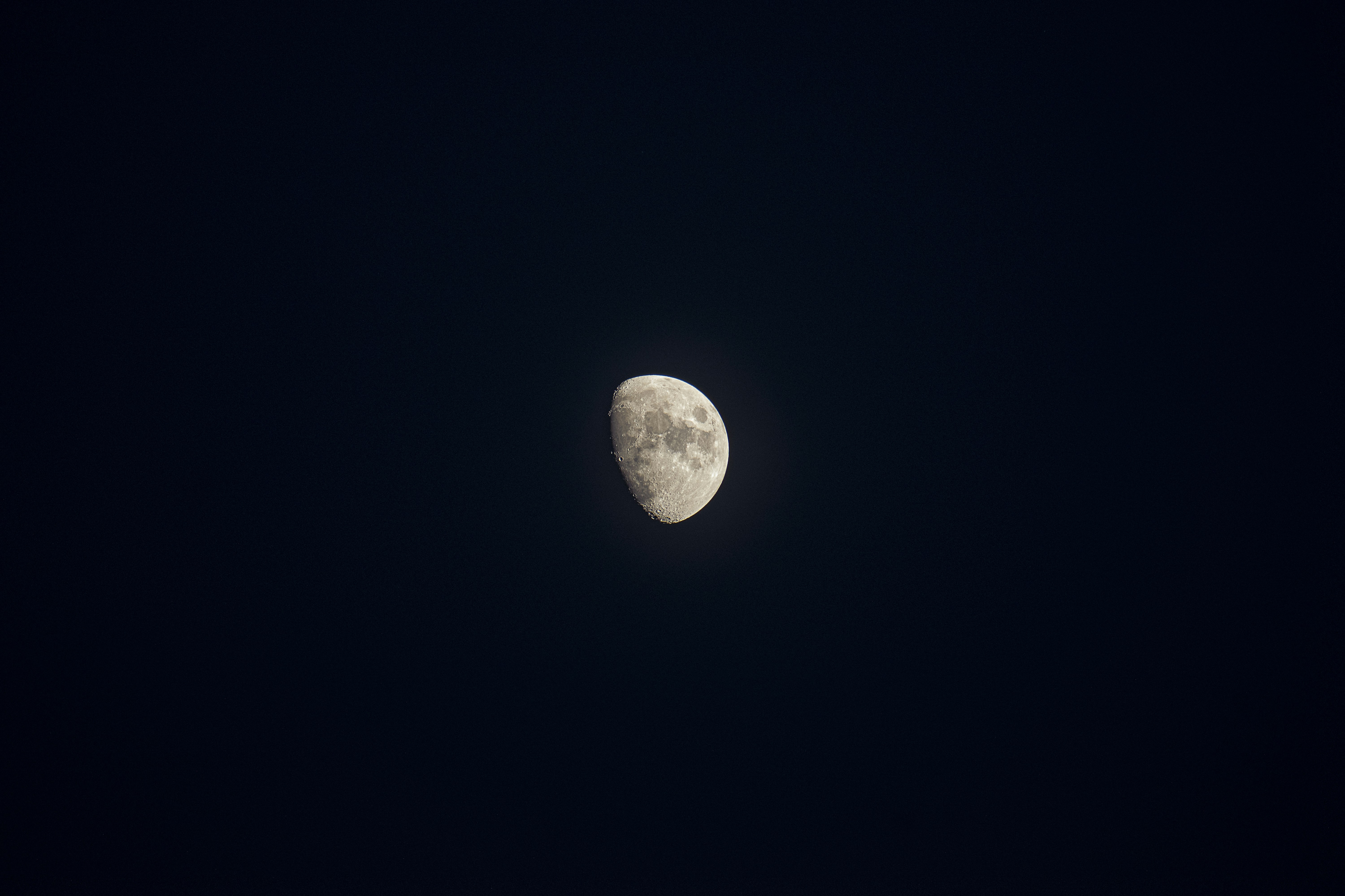 Waxing crescent moon illuminated against a deep navy sky, showcasing its craters and textures.