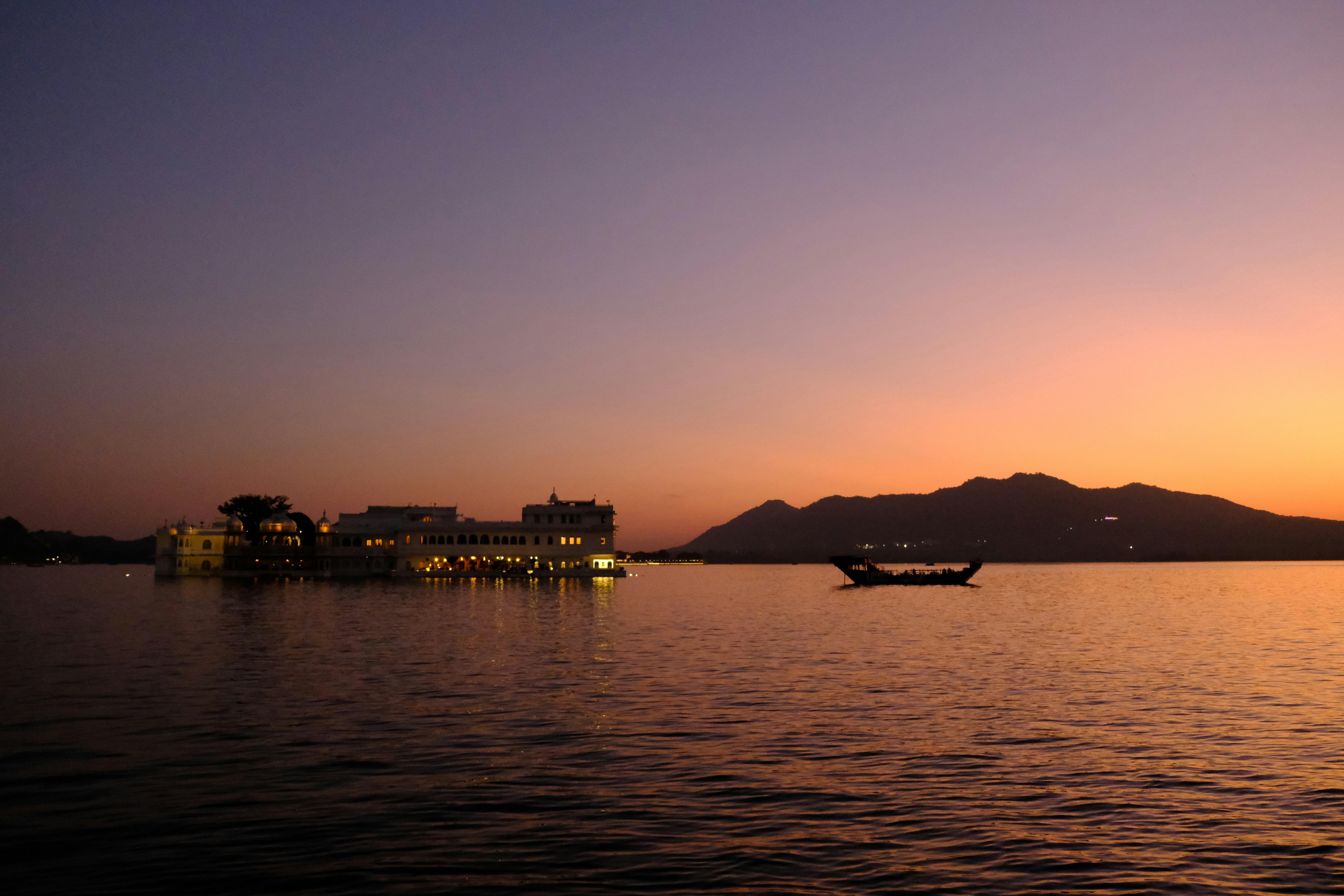 Harbor at Dusk: Lantern-lit Wharf and a Silent Boat Under Peach-Orange Skies