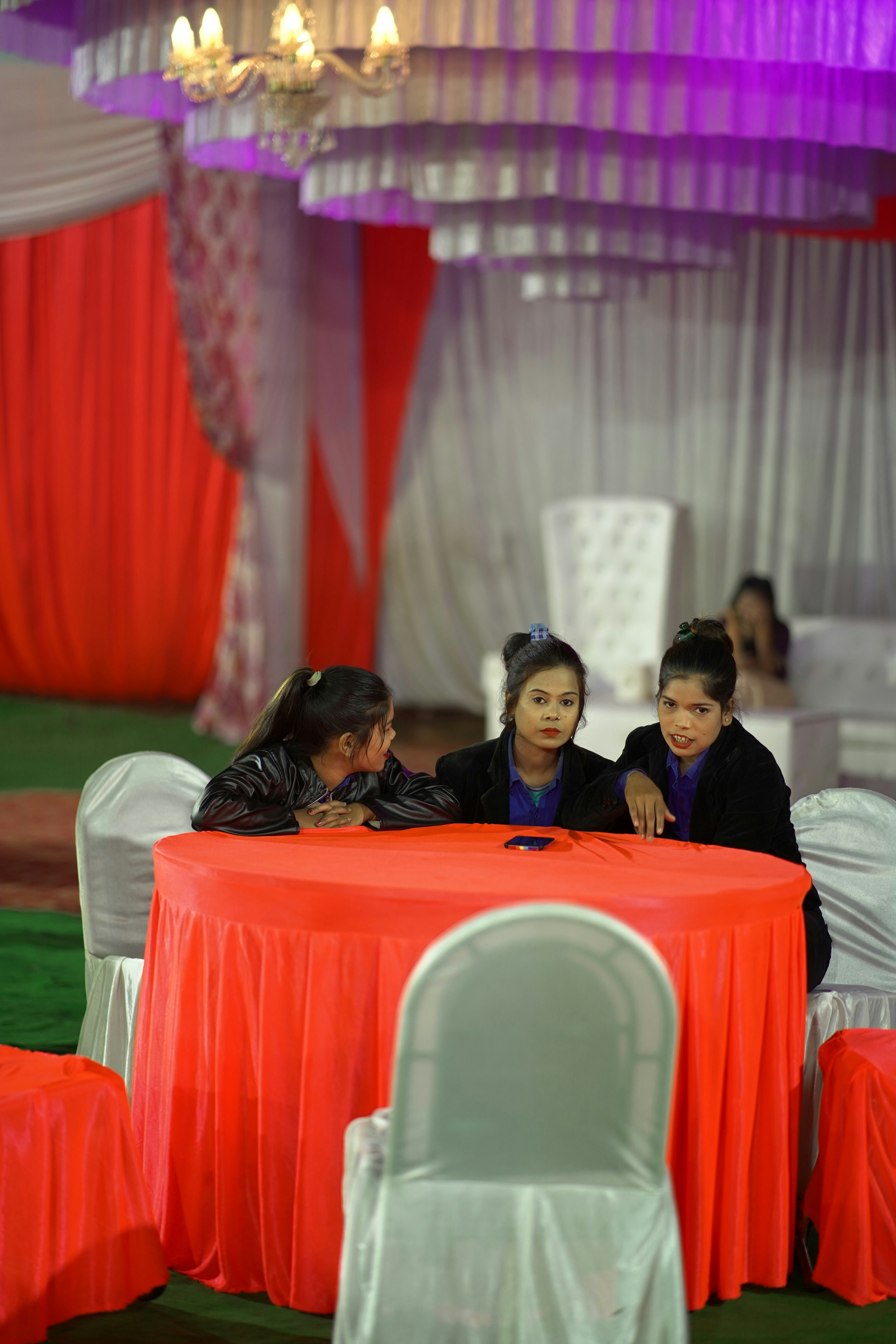 Crimson Tabletalk: Three Friends at a Velvet-Lit Round Table
