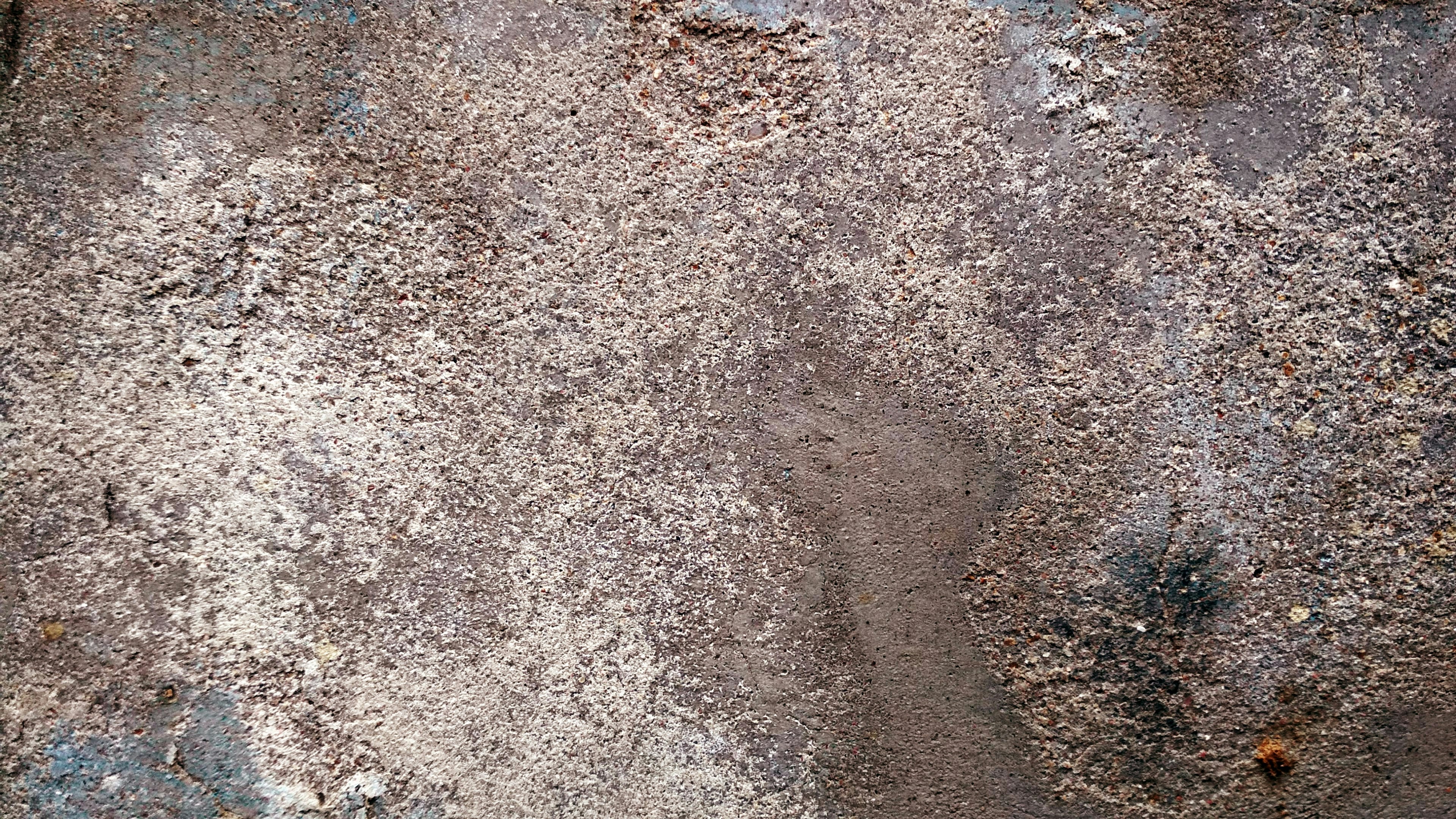 Textured surface of weathered concrete displaying a mix of earthy tones and subtle patterns. Ideal for background use or abstract art.