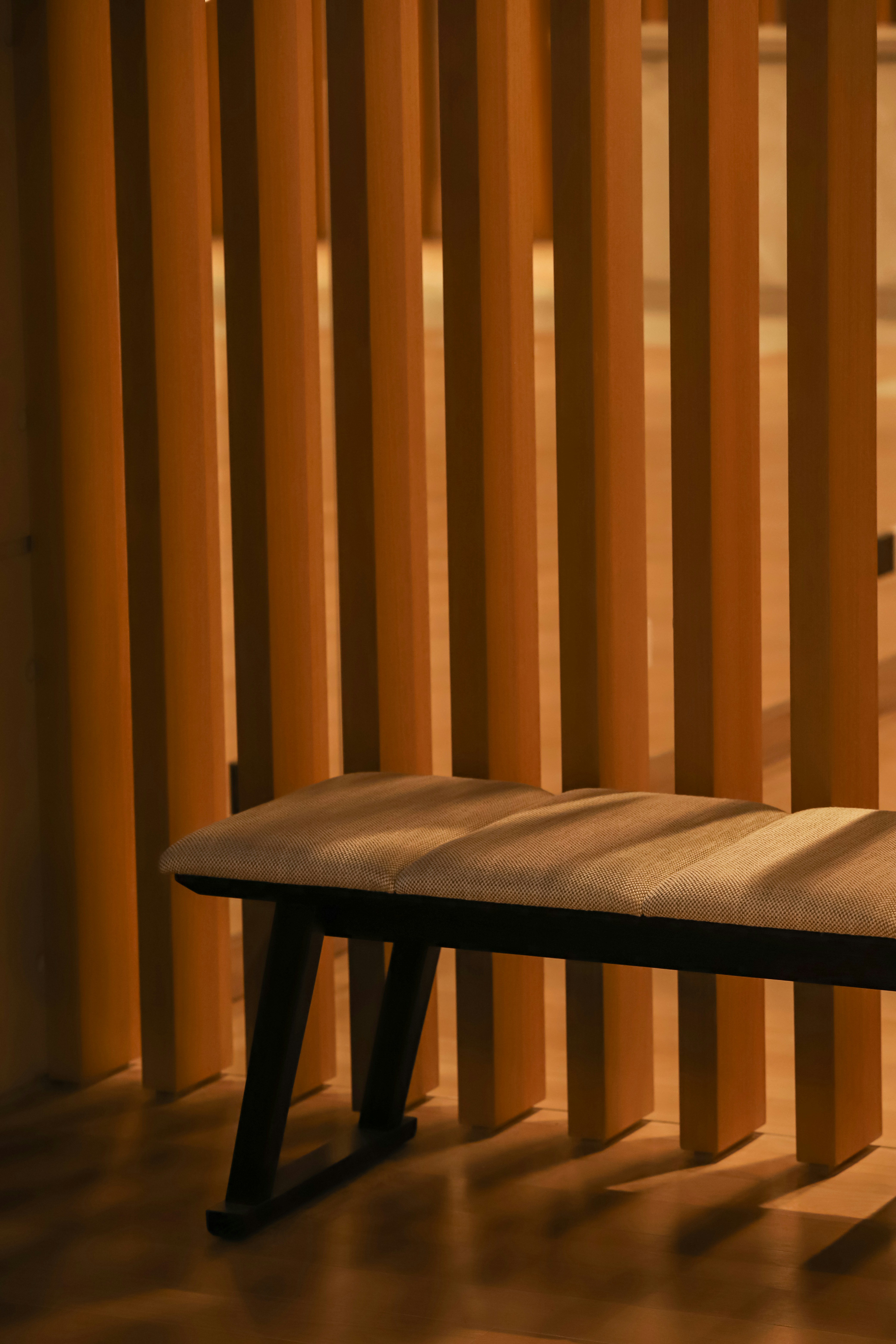 Warm-toned bench under vertical slats in quiet interior