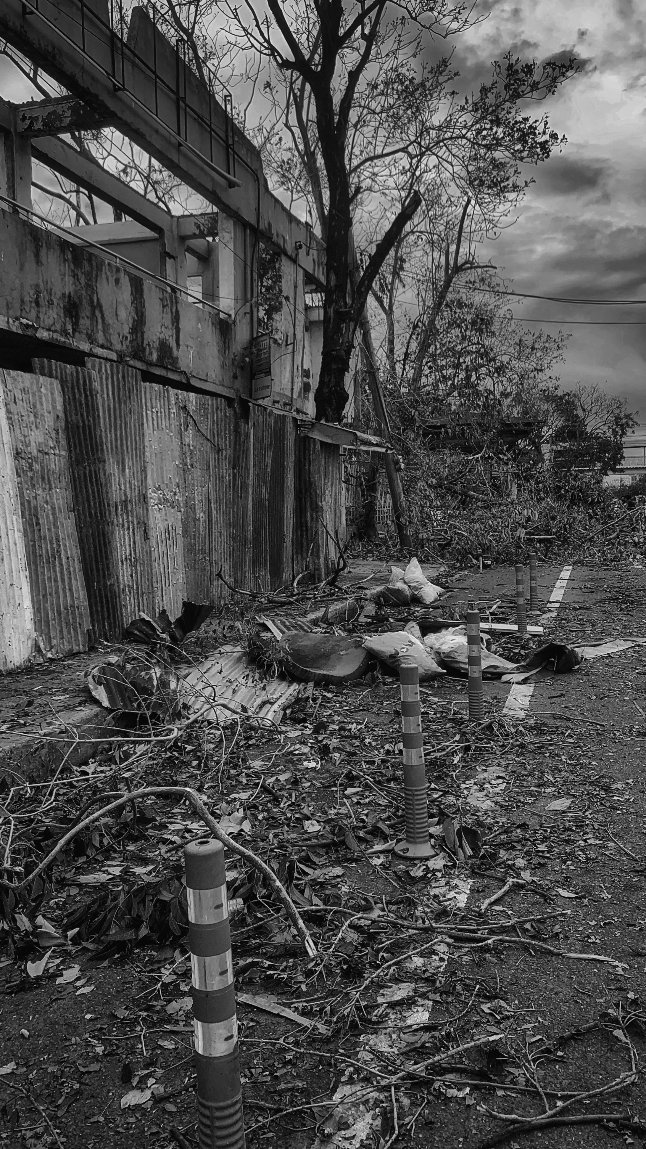 Ruinous Alley: Debris, Striped Poles, and a Weathered Fence