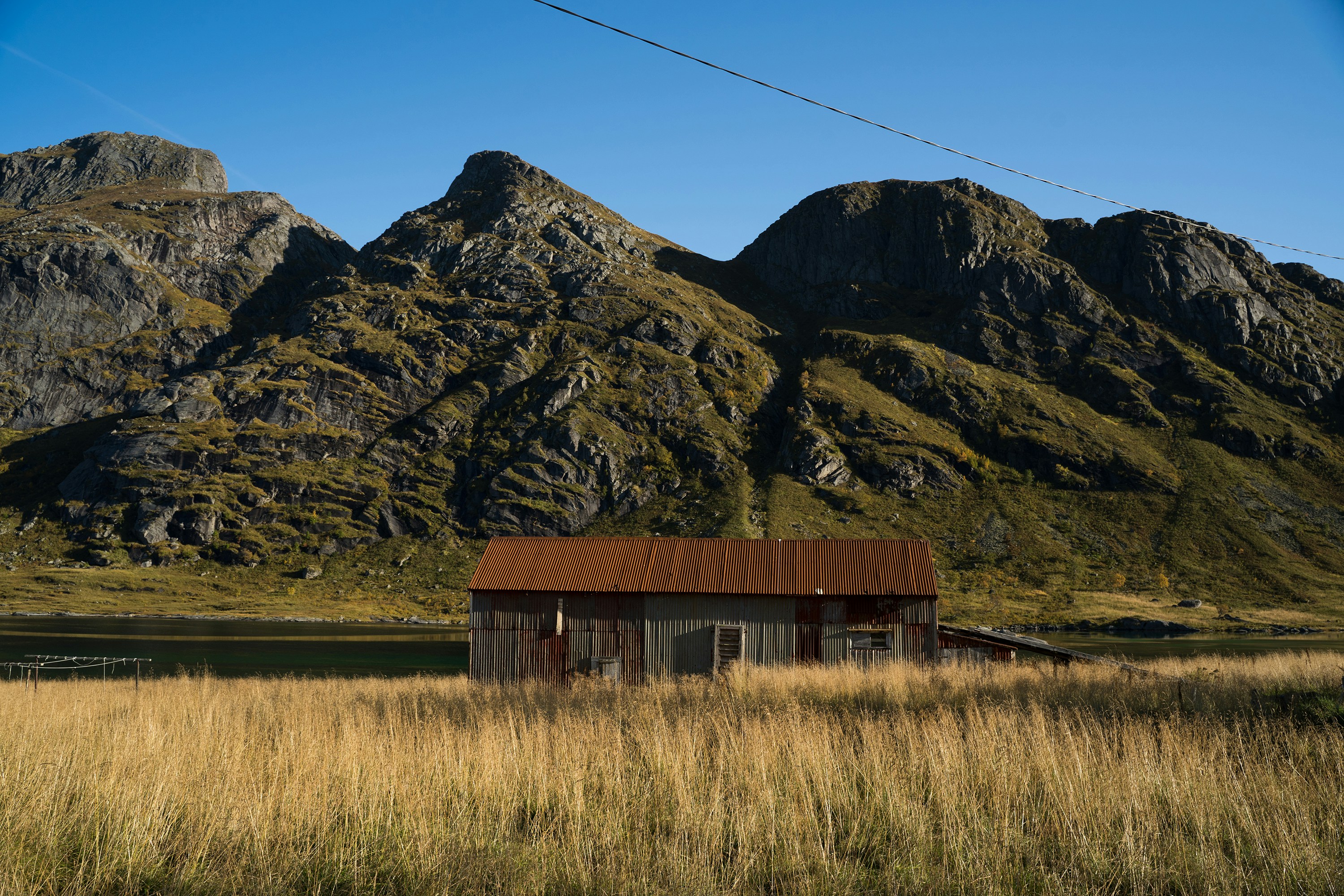 Rusty-roofed shed at the foot of rugged hills