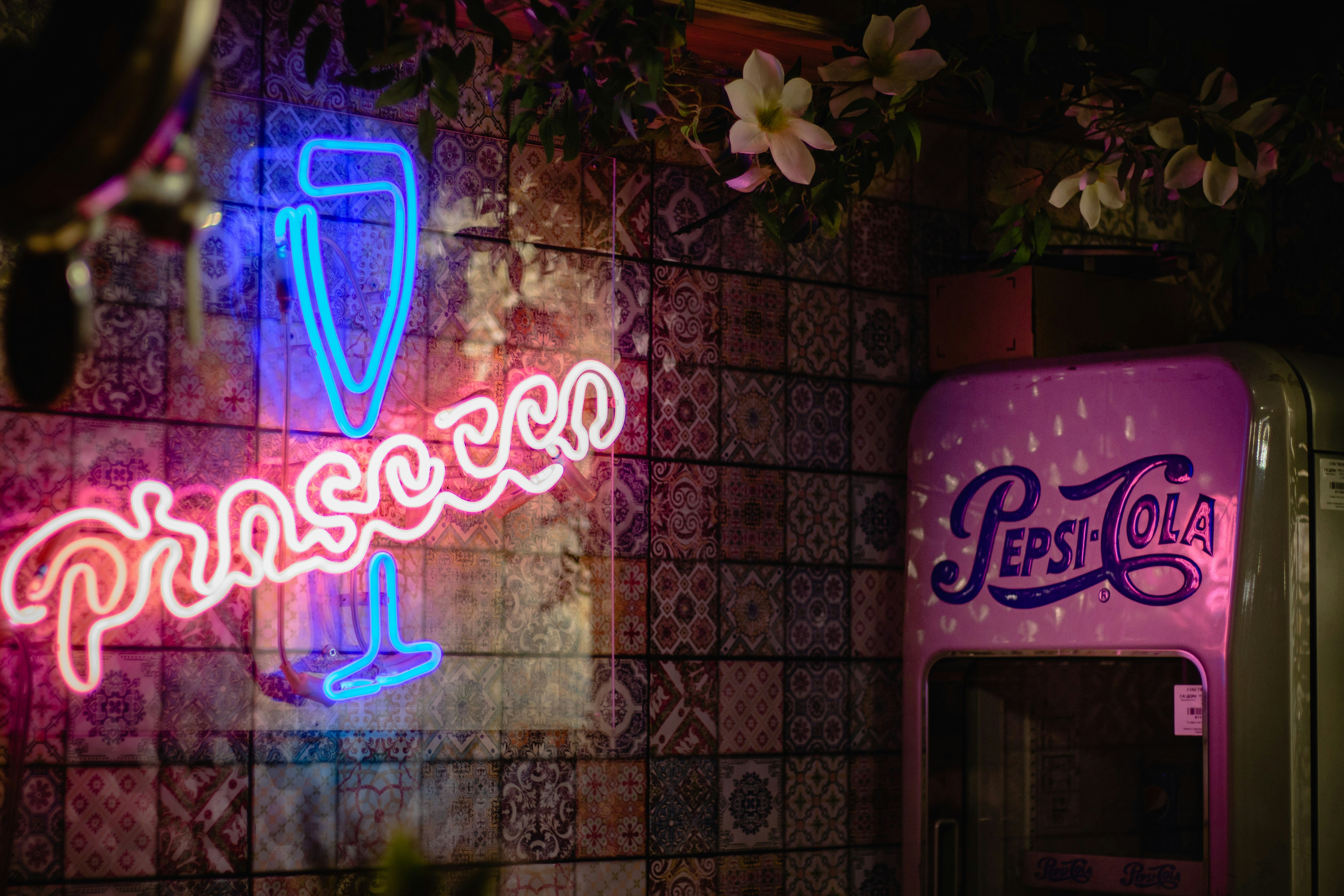 Une machine à cola Pepsi rose assise à côté d’une enseigne au néon ...