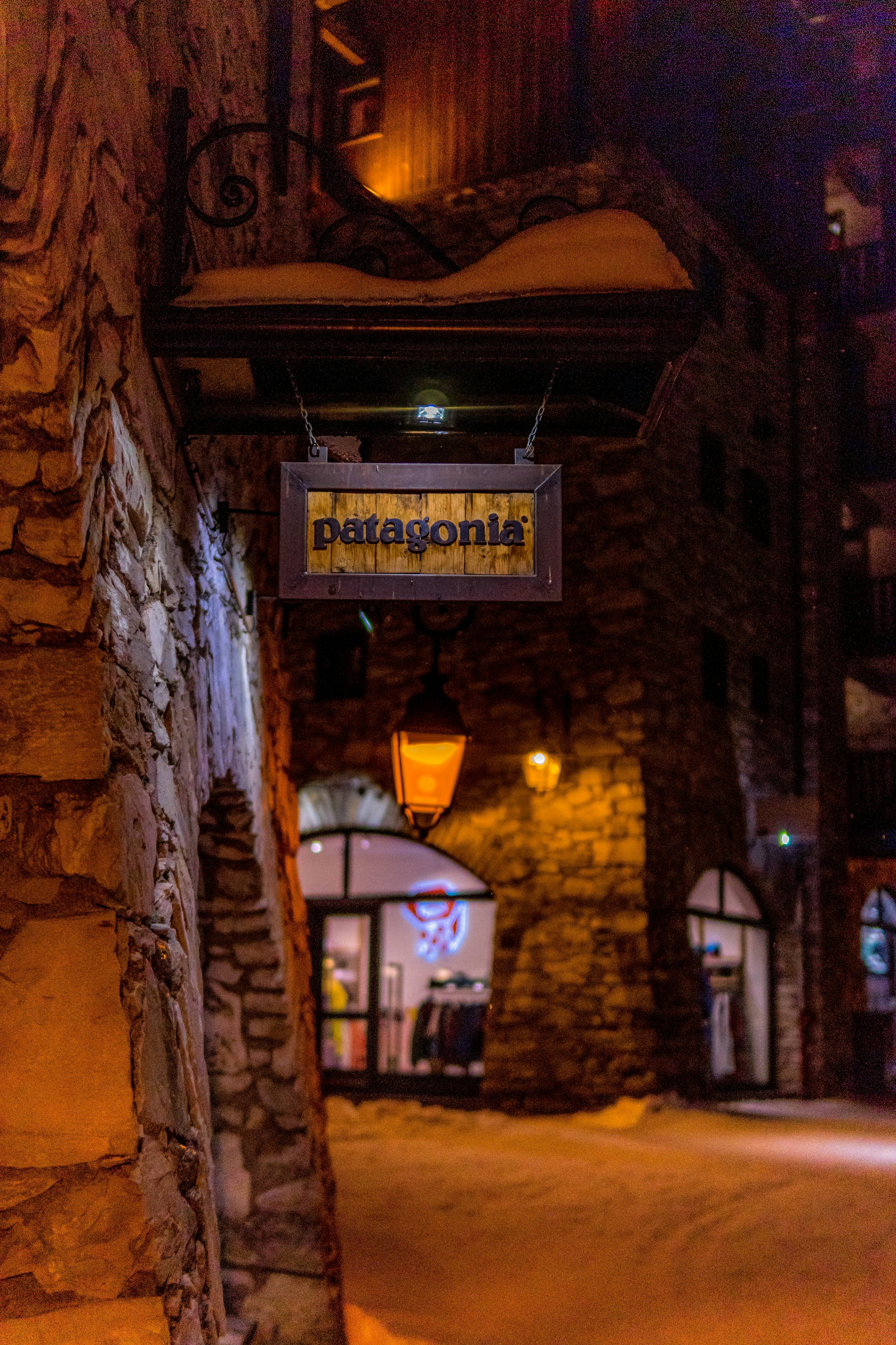 Patagonia Sign in a Snowlit Alpine Alley Under Amber Lanterns