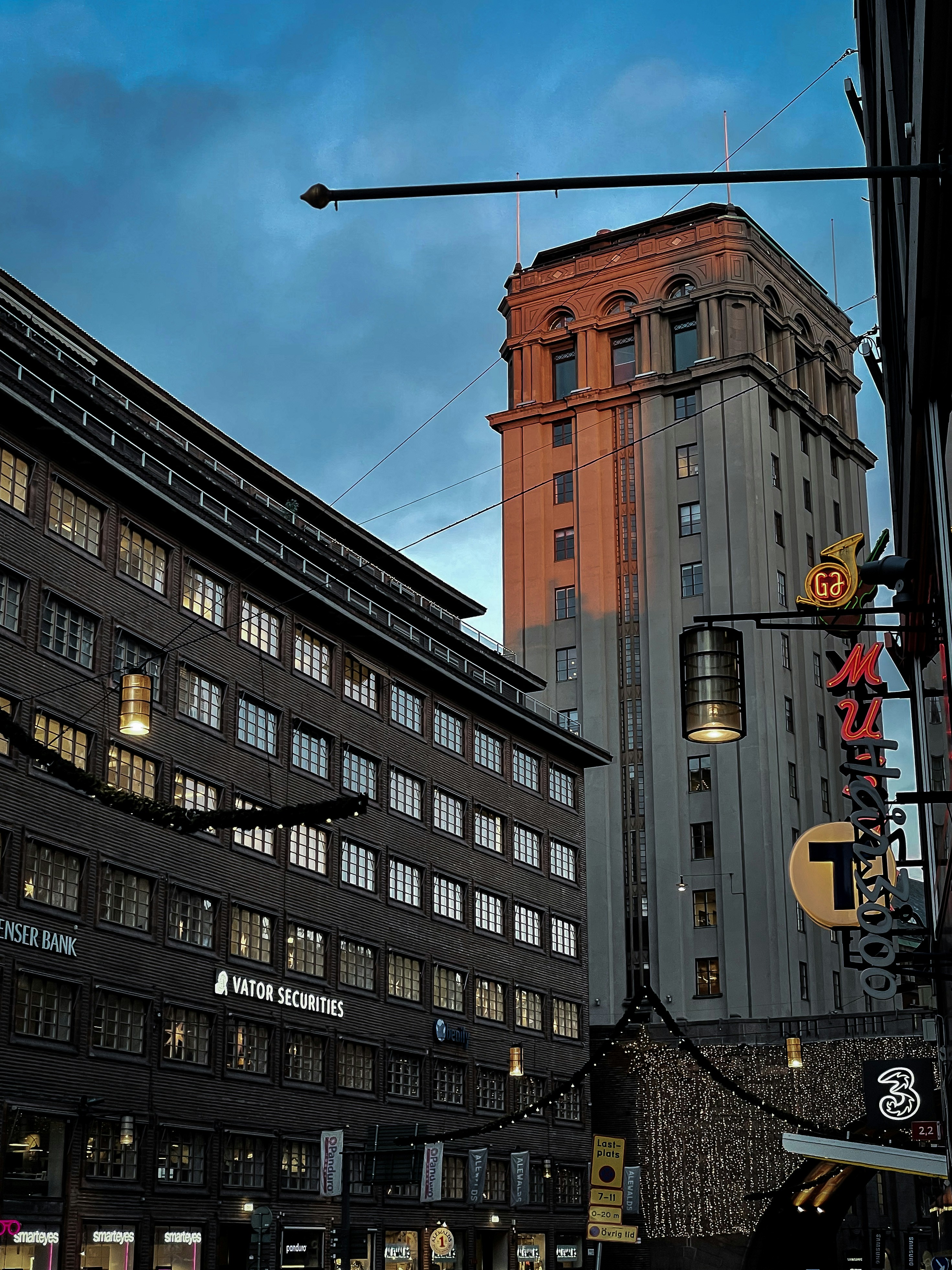Orange-Crowned Tower Rising Over a Brick-Lined City Block at Dusk