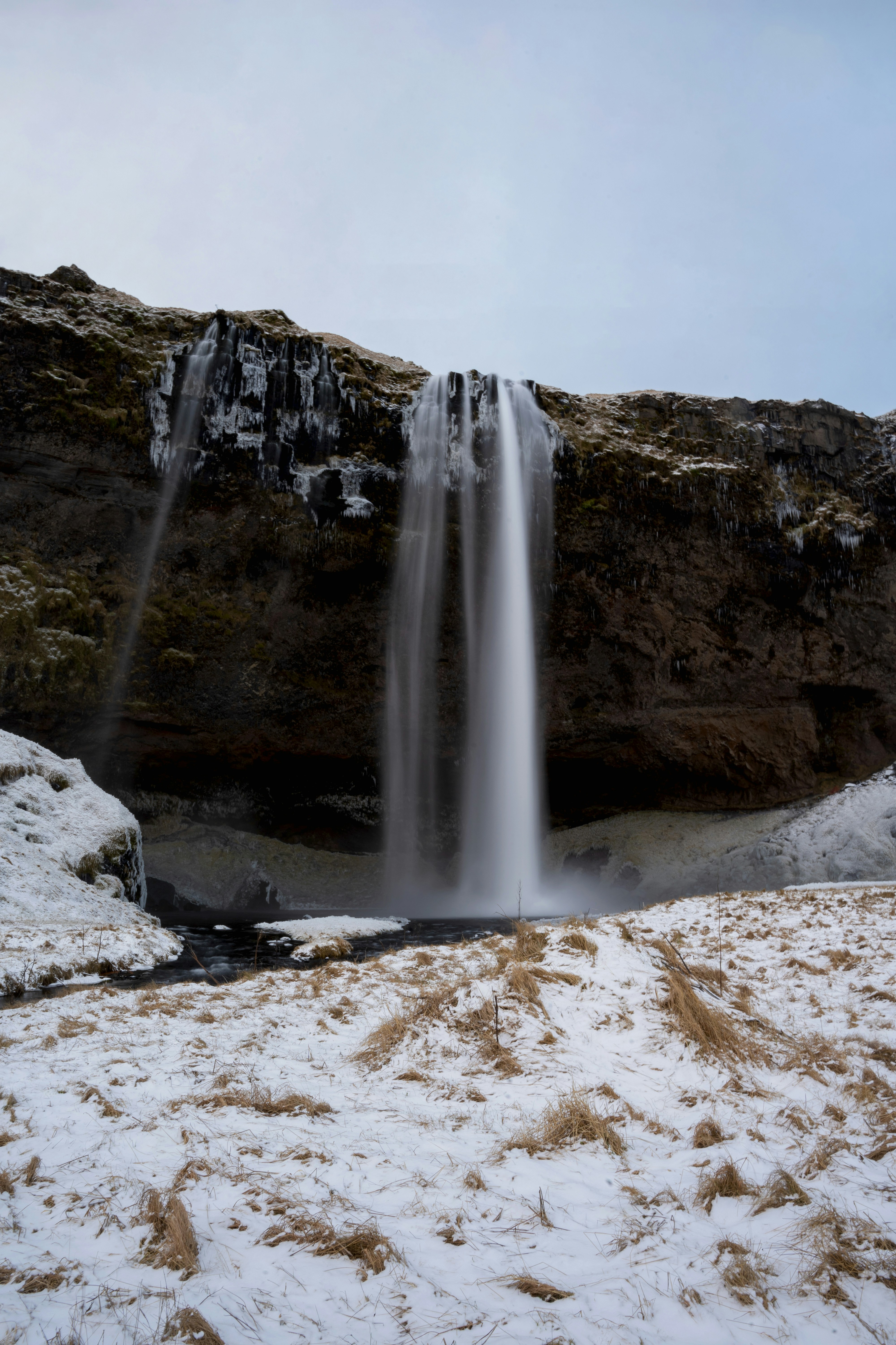 A very tall waterfall in the middle of a snowy field photo – Free ...