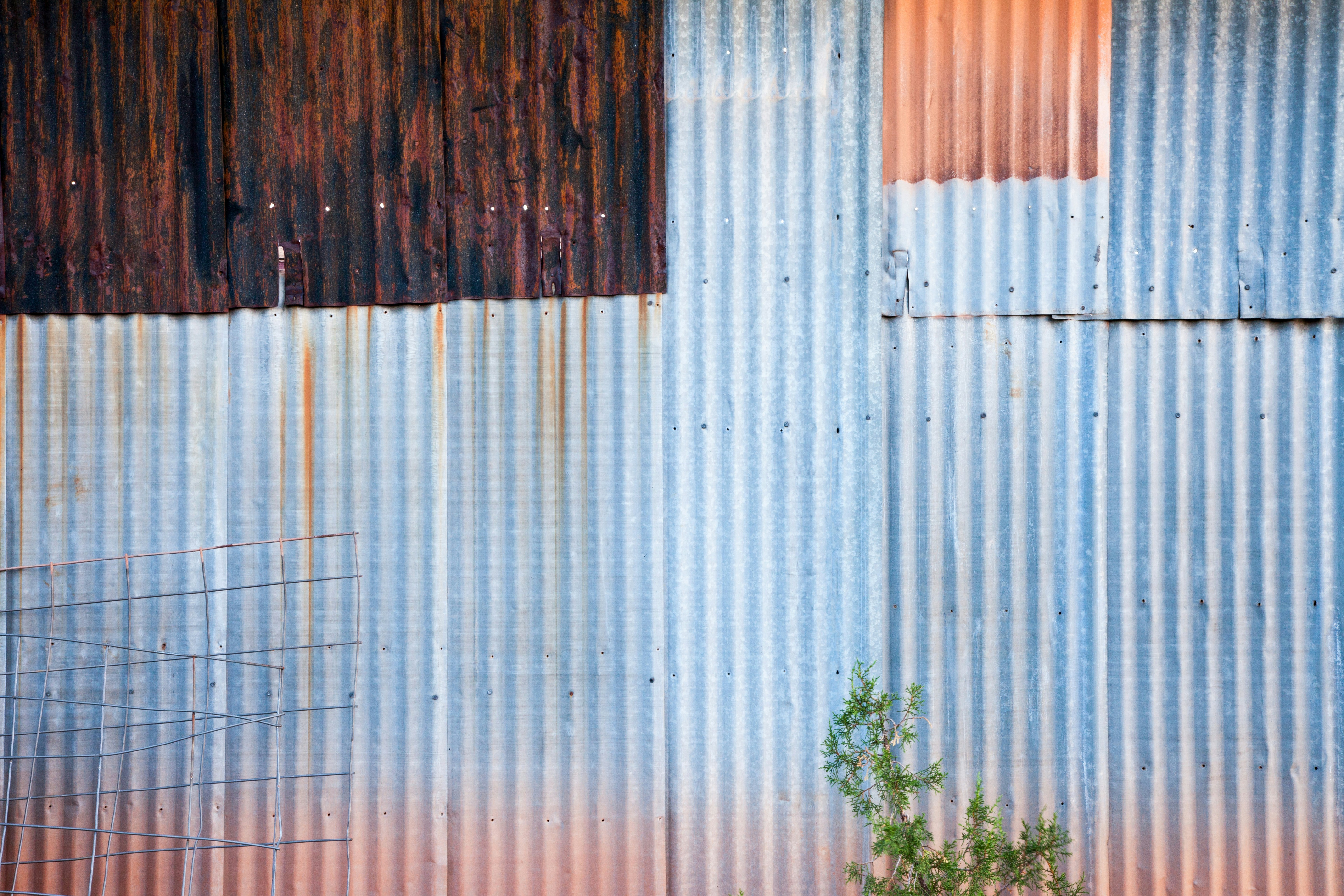 A rusted metal building with a tree in front of it photo – Free Texture ...
