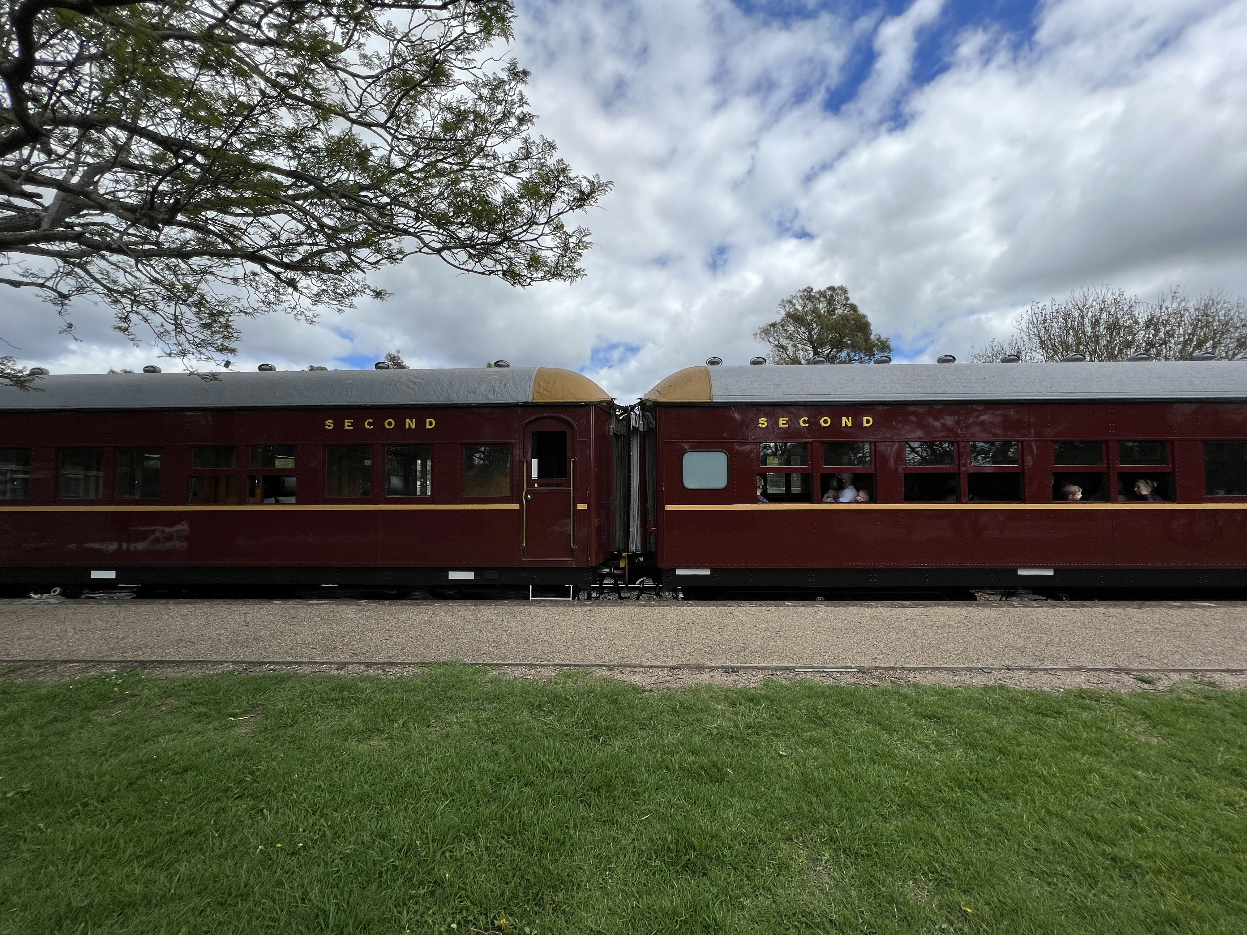 Midday on the Rails: Two Vintage Red Coaches Rest Along a Quiet Track
