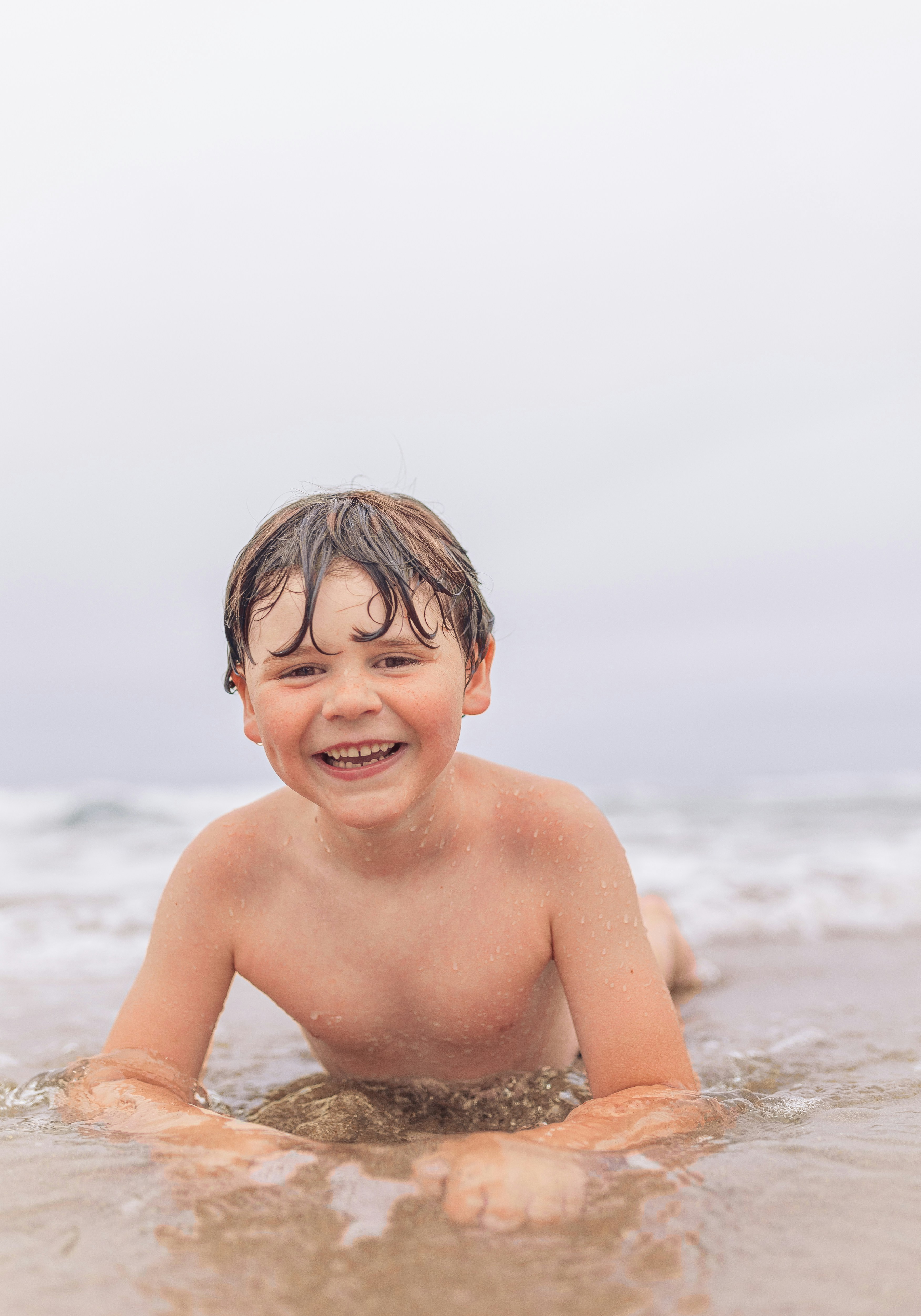 A young boy is playing in the water at the beach photo – Free ...