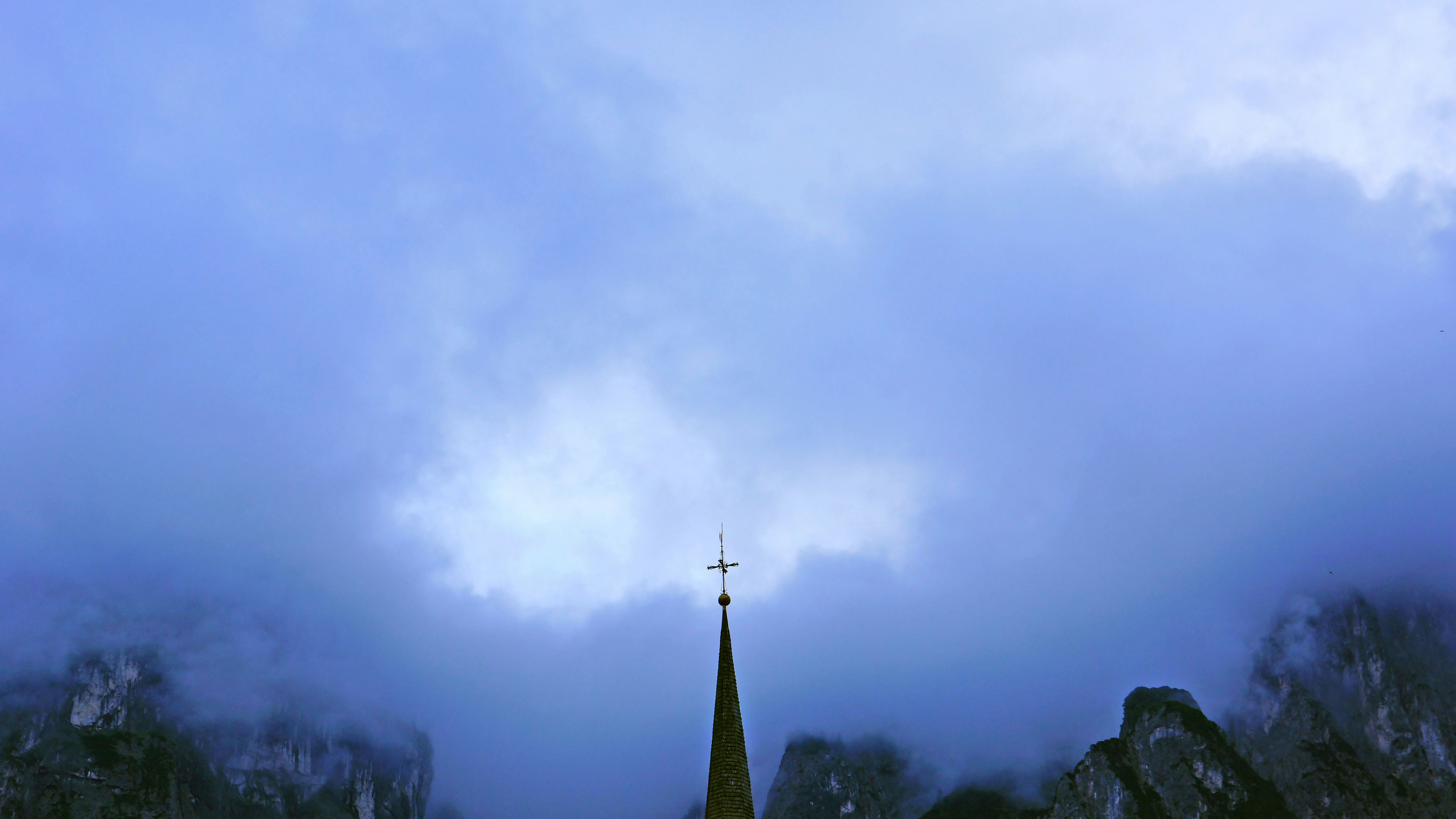 Cross Above the Fog: A Lone Spire Piercing the Alpine Mist
