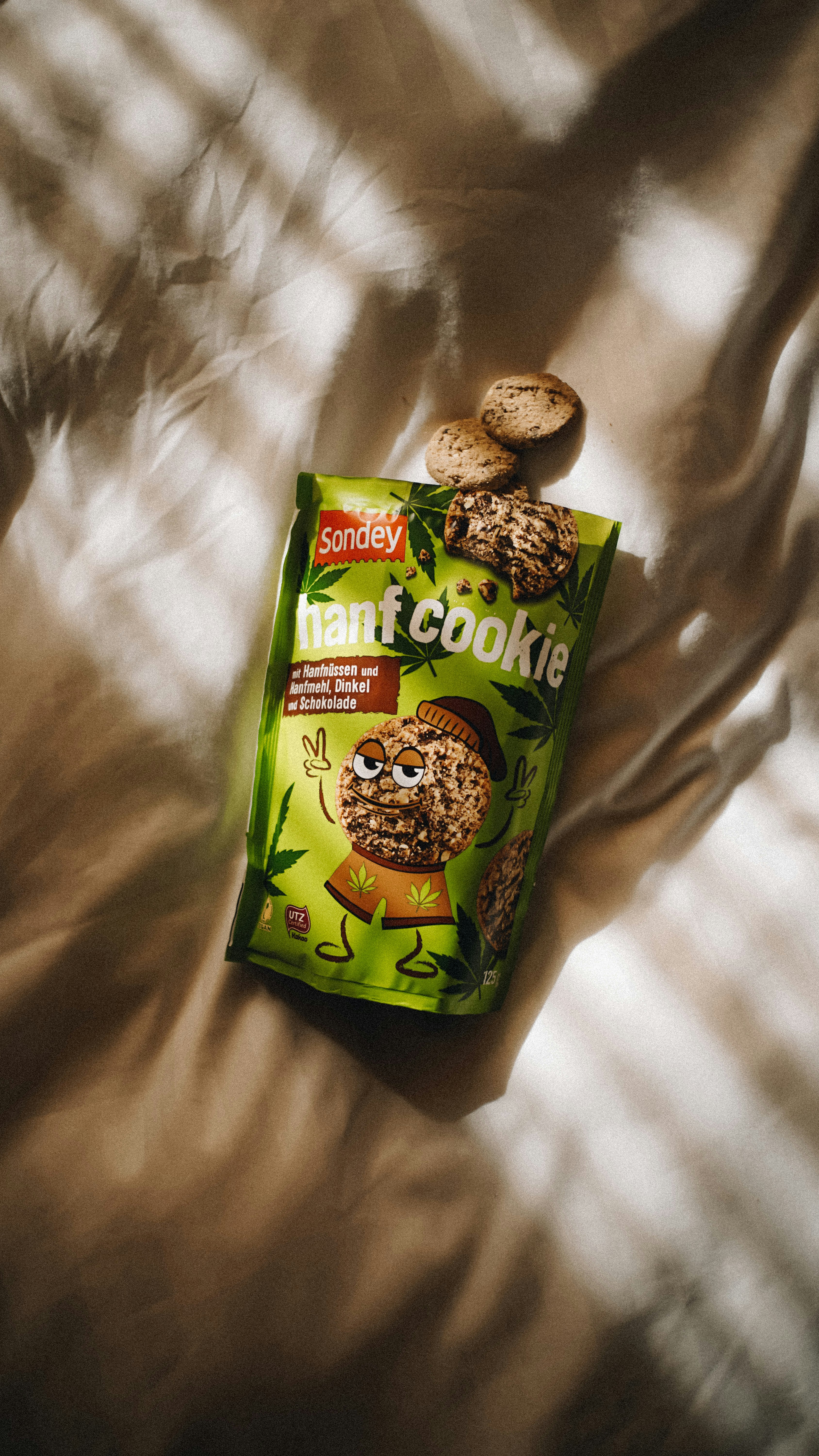 Cartoon Cookie Mascot on a Bright Green Snack Package Resting on Soft Beige Fabric