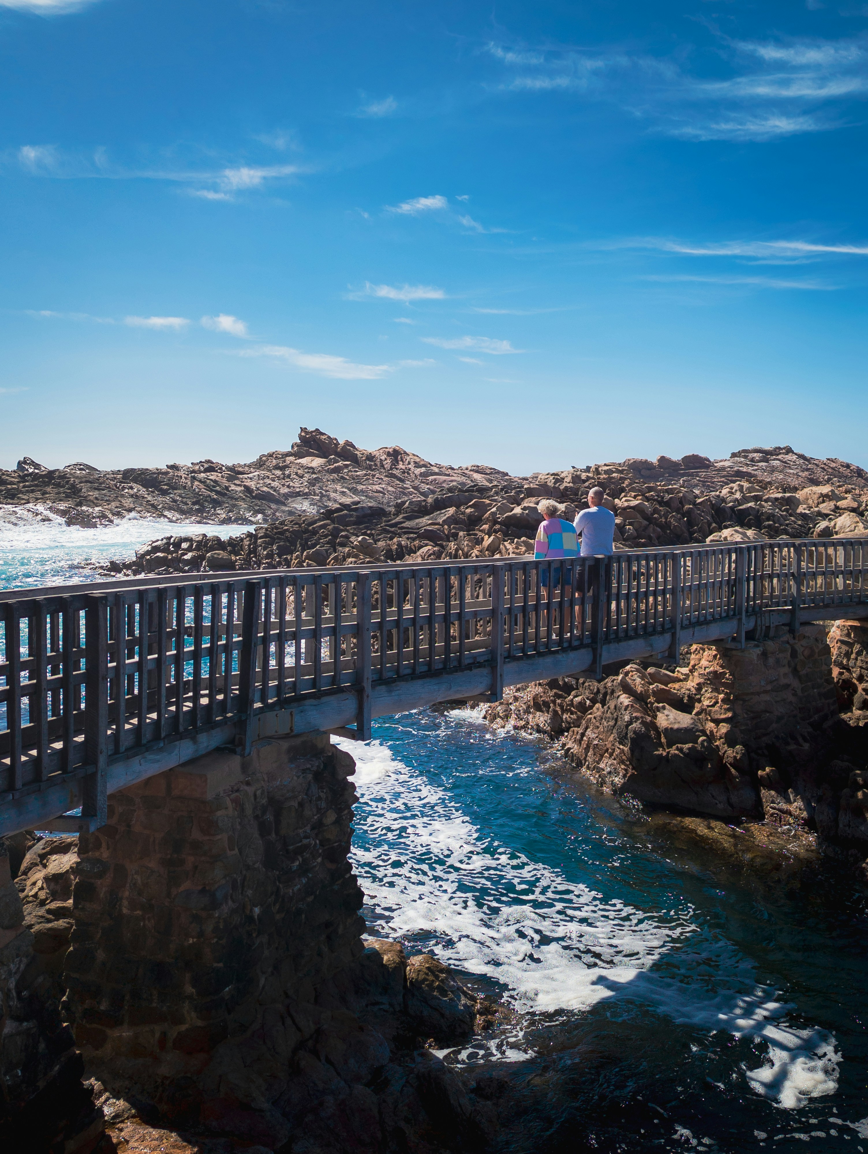 Two Figures on a Coastal Bridge Over Rugged Rockscape