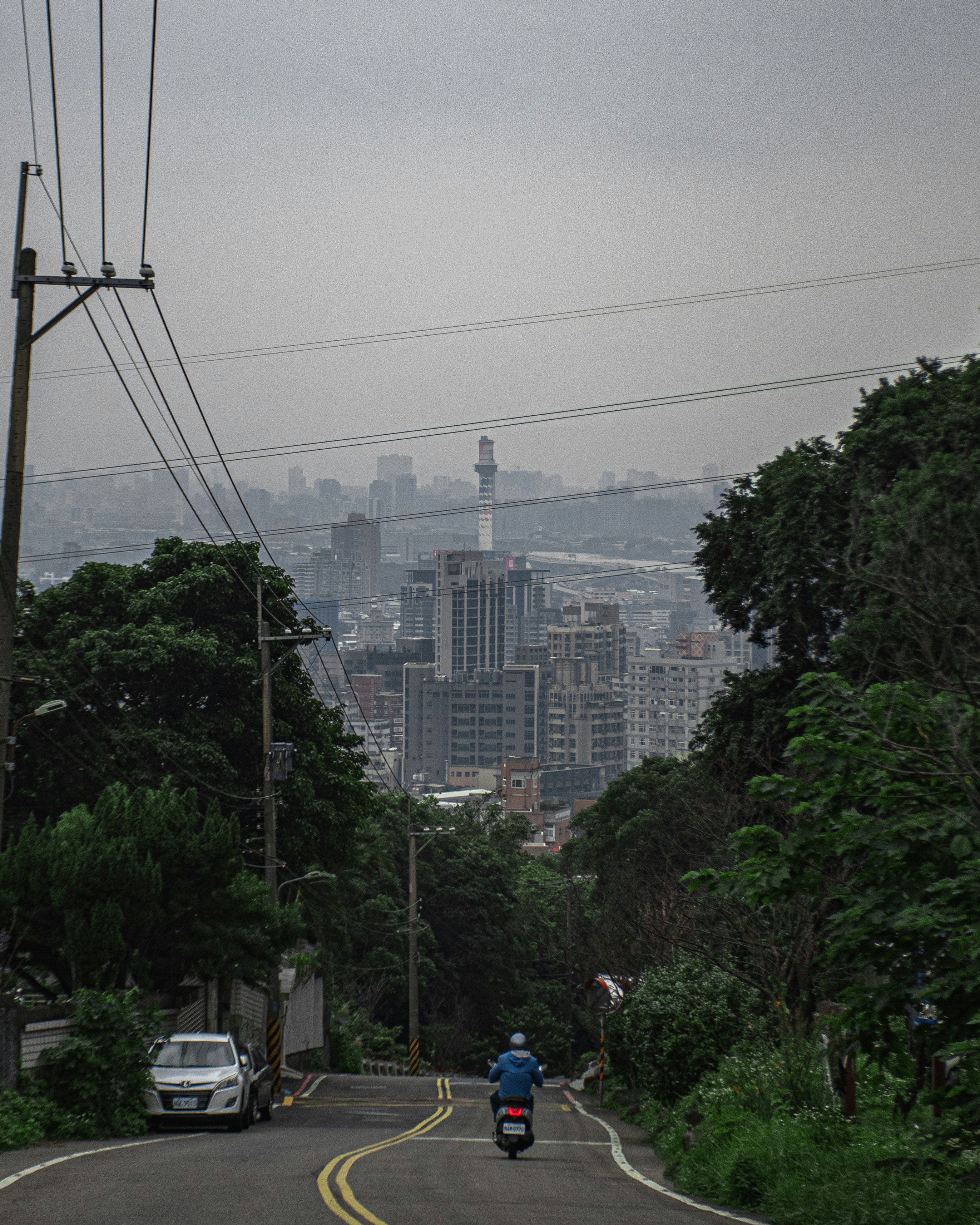Winding Descent: A Scooter Carves a Quiet Path Toward the Distant Skyline