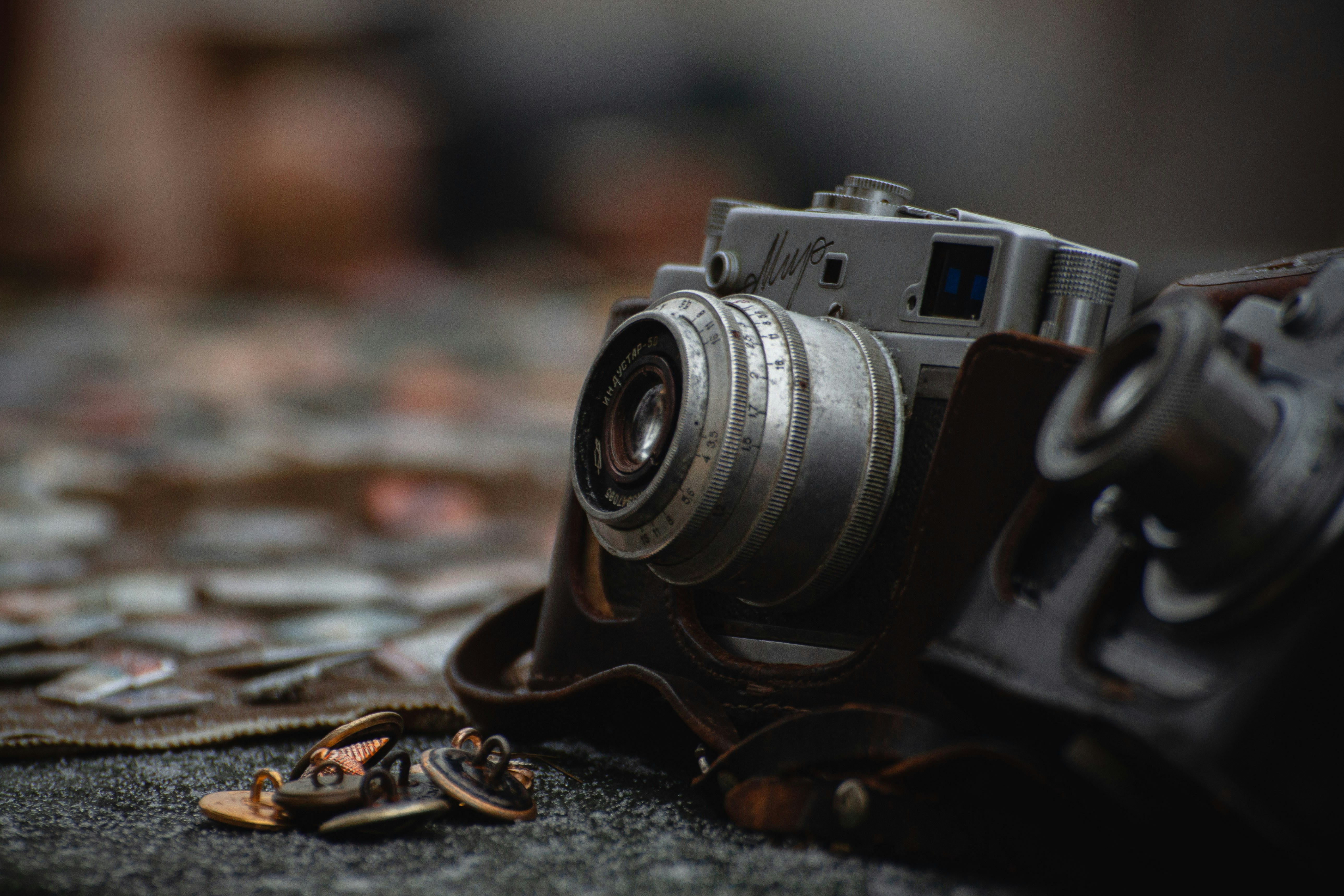Vintage cameras resting on a textured surface, surrounded by scattered photographs, evoking a sense of nostalgia for classic photography.