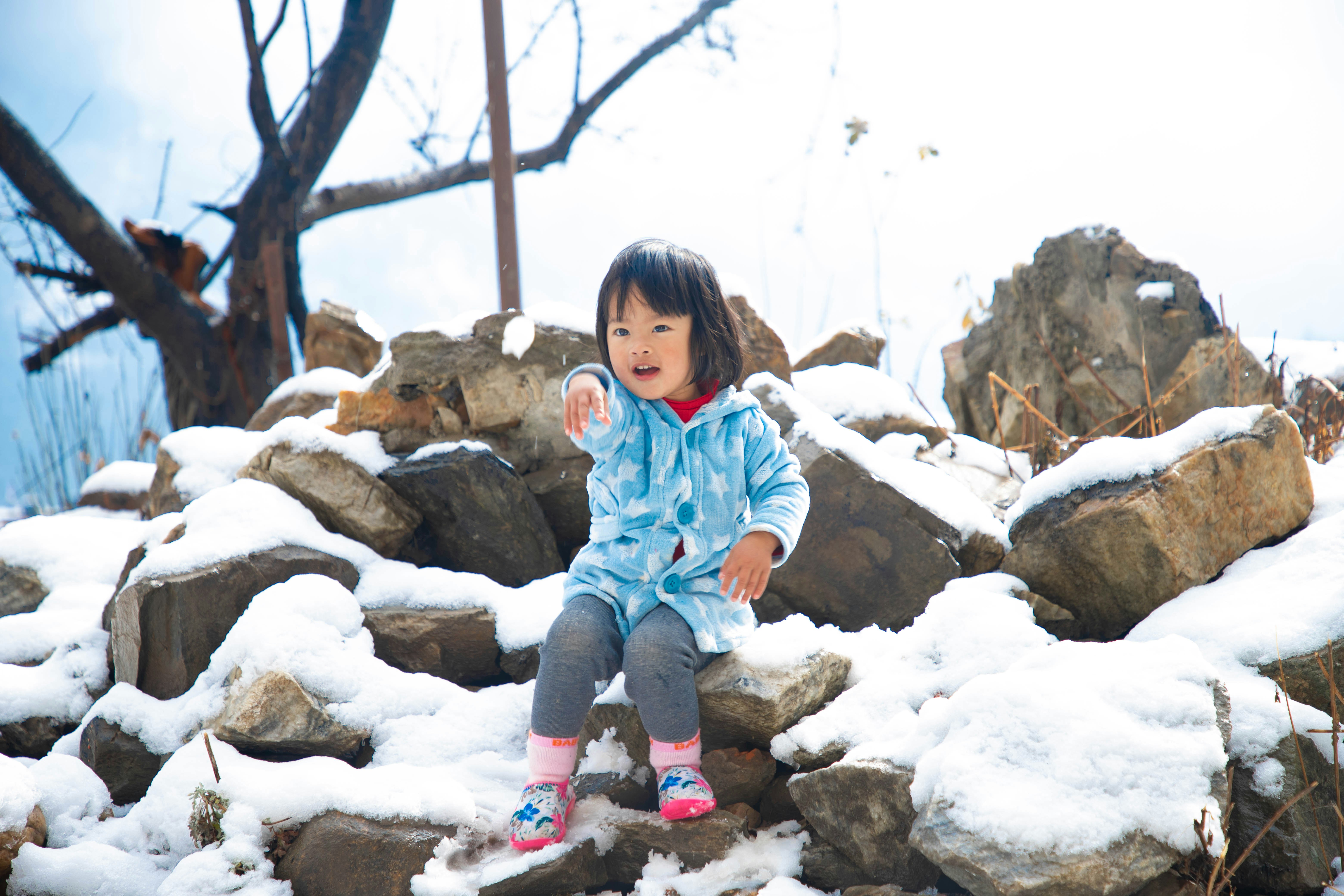 A little girl sitting on top of a pile of snow photo – Free Thimphu ...