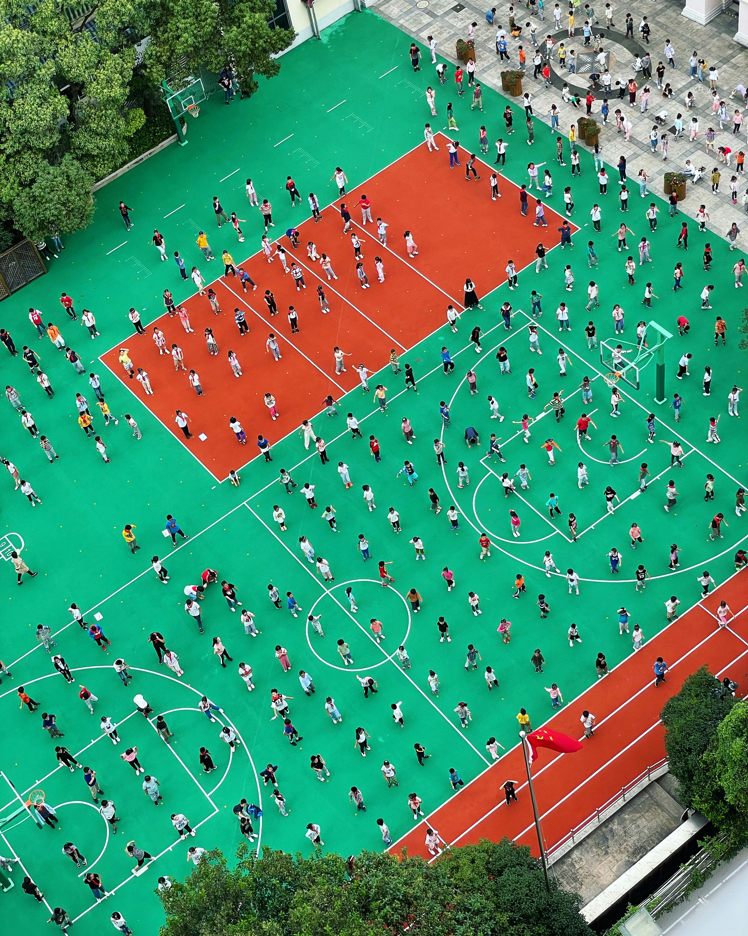 Aerial view of a bustling sports complex filled with people engaging in various activities on vibrant green and red courts.