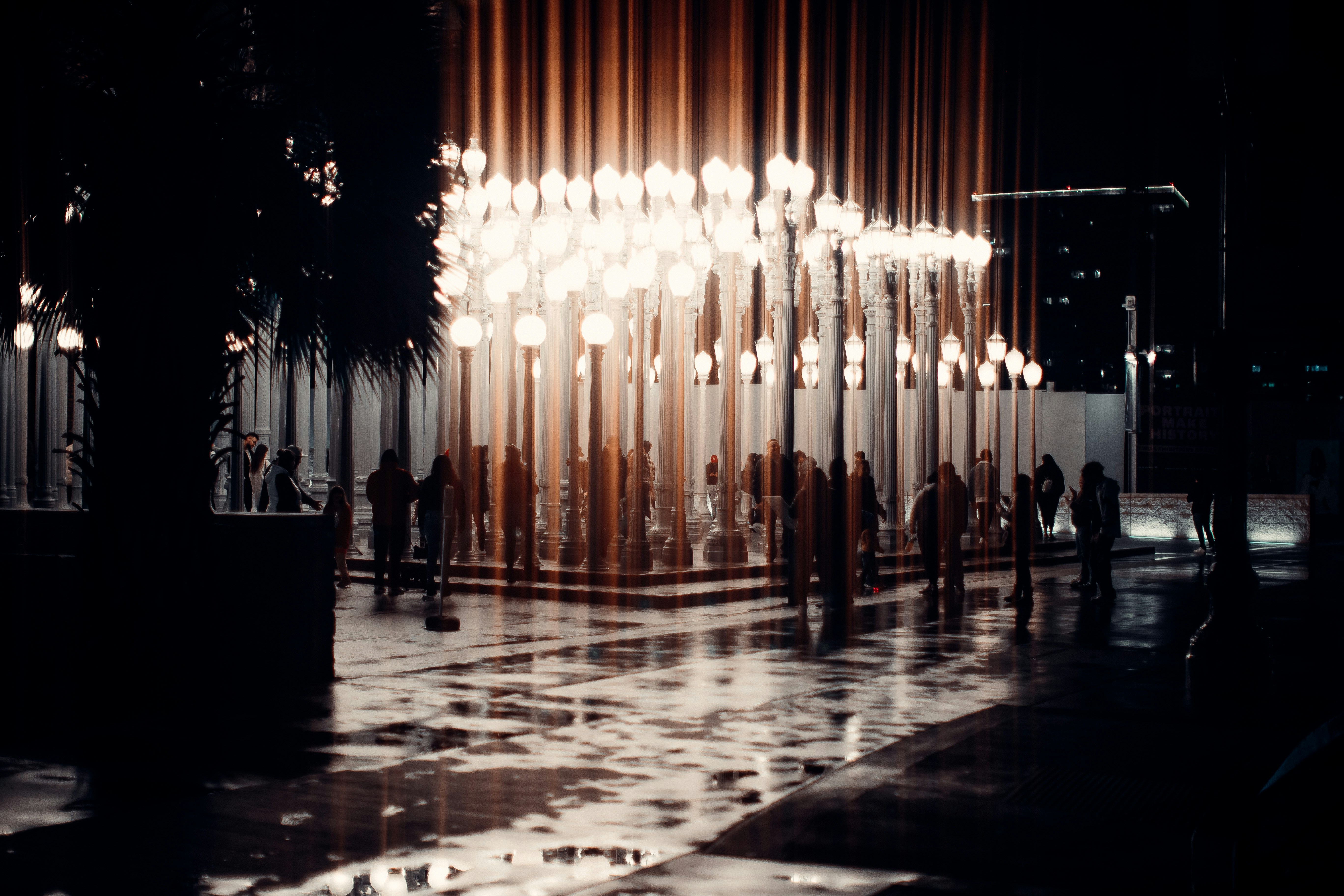 a group of people standing in front of a tall light fixture