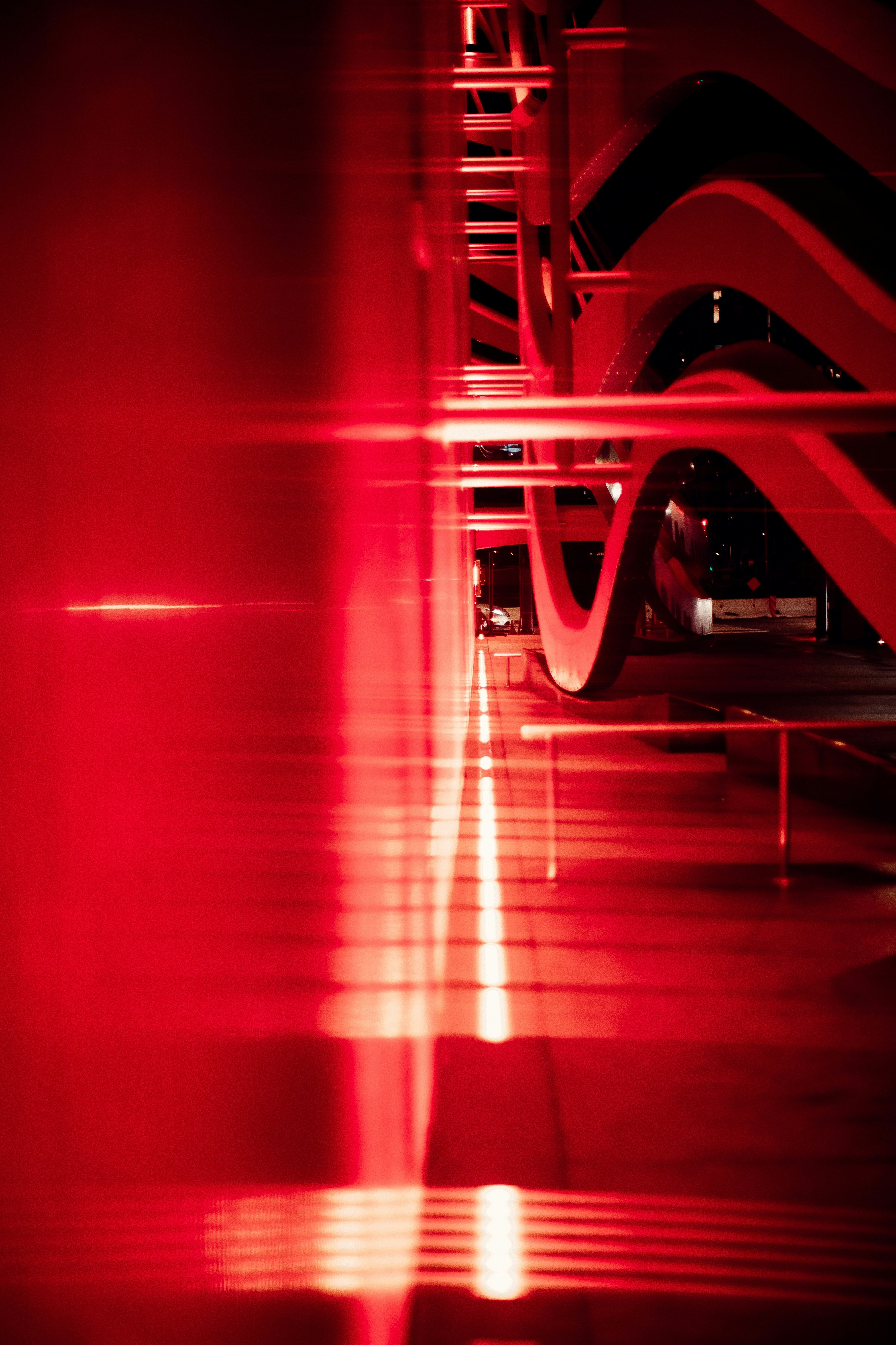Crimson Ribbons: Neon Loops Surround a Silent Structure