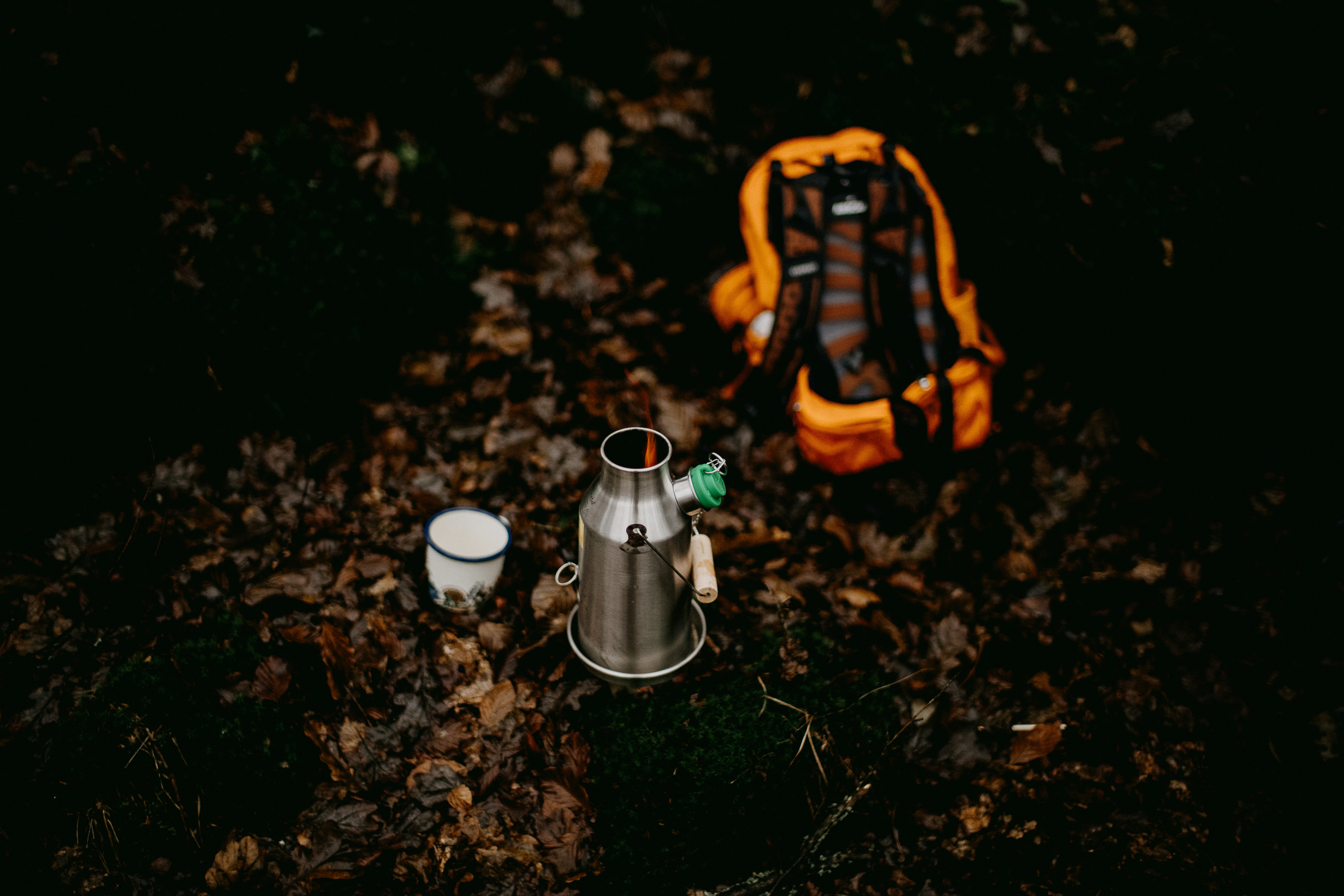 Autumn Camp Essentials: Stainless Kettle and Orange Pack Rest on Leaf-Litter
