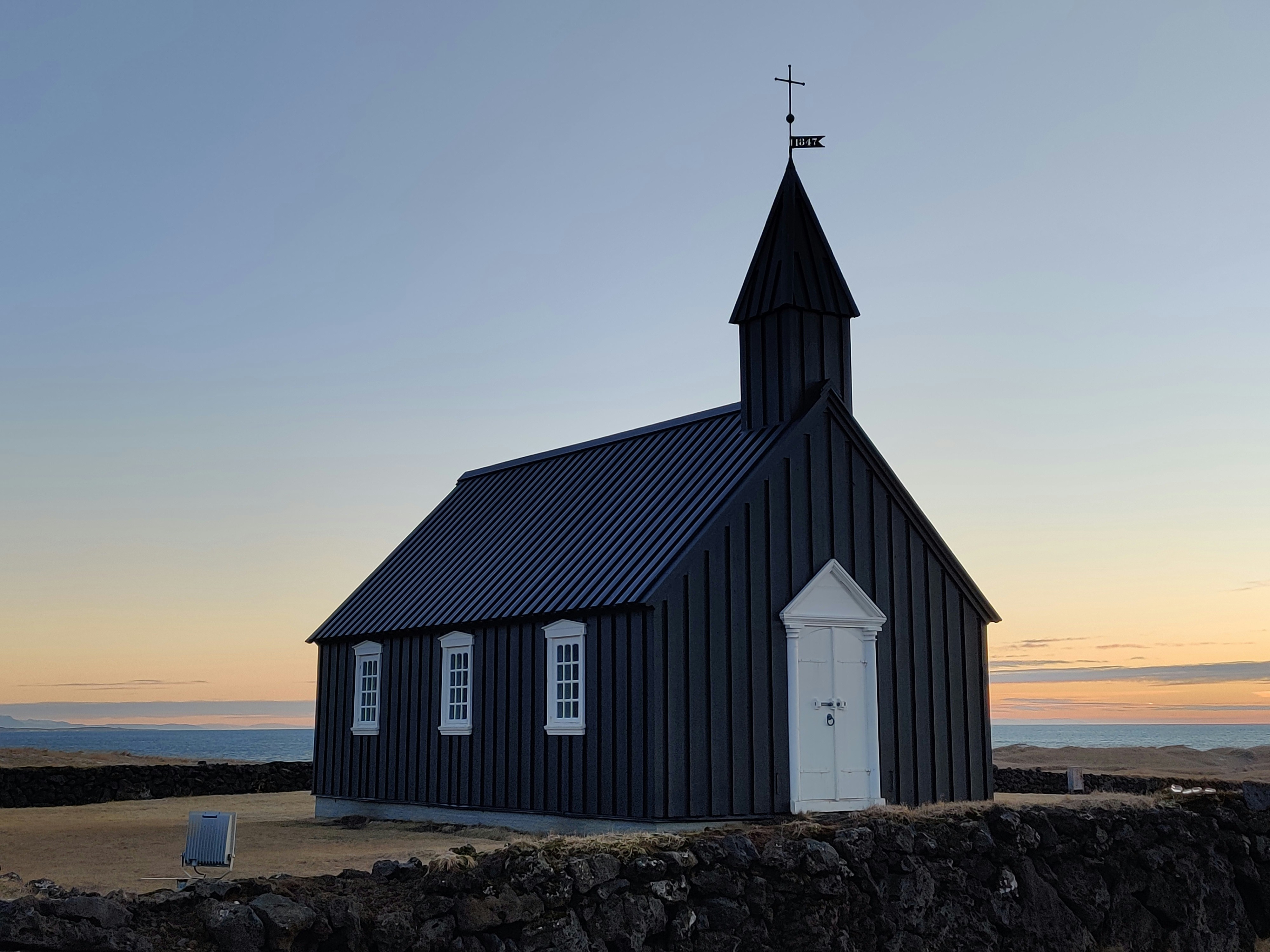 A small black church with a steeple and a cross on top photo – Free ...