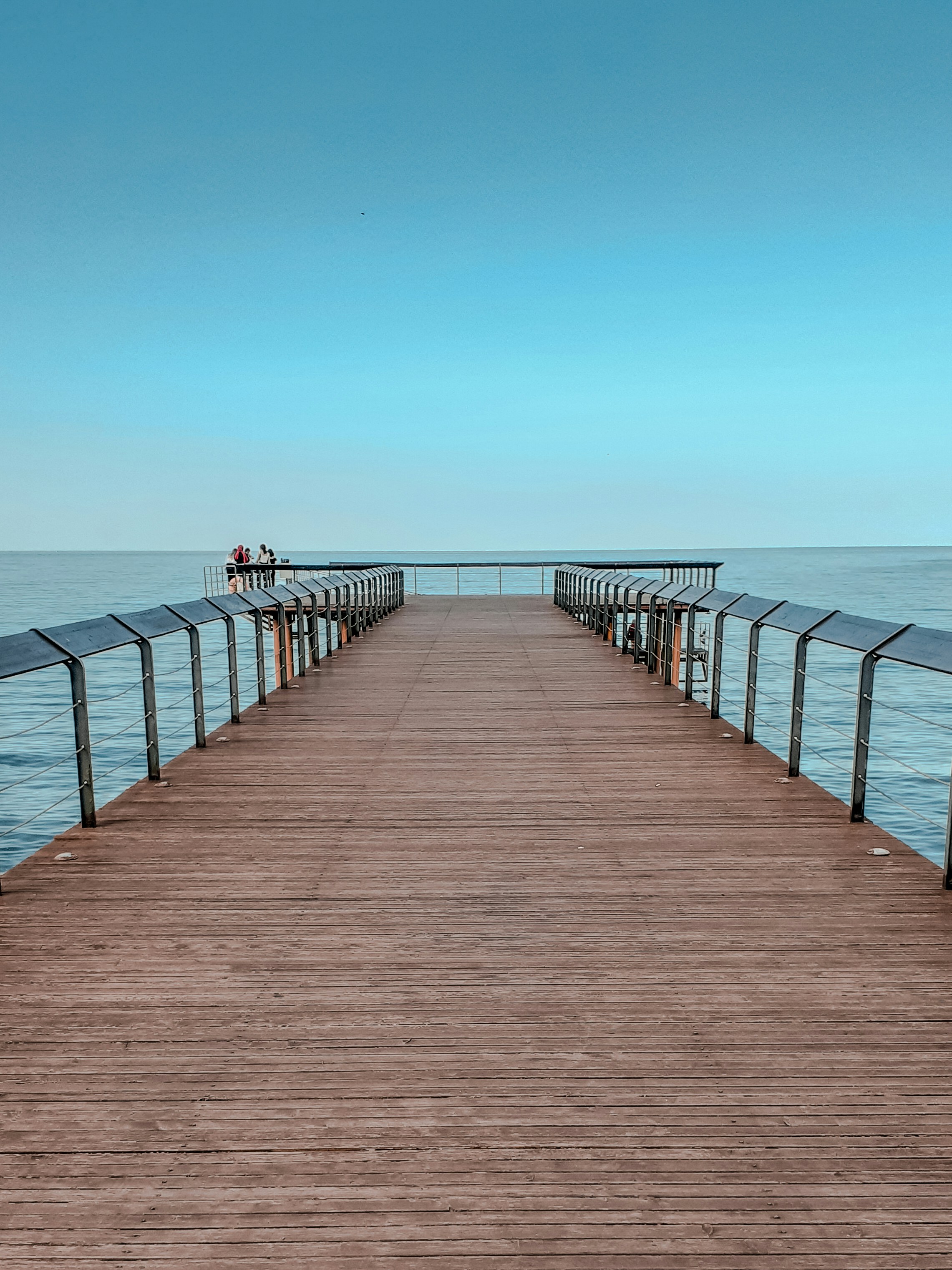 A wooden pier with railings leading into the ocean photo – Free Ordu ...