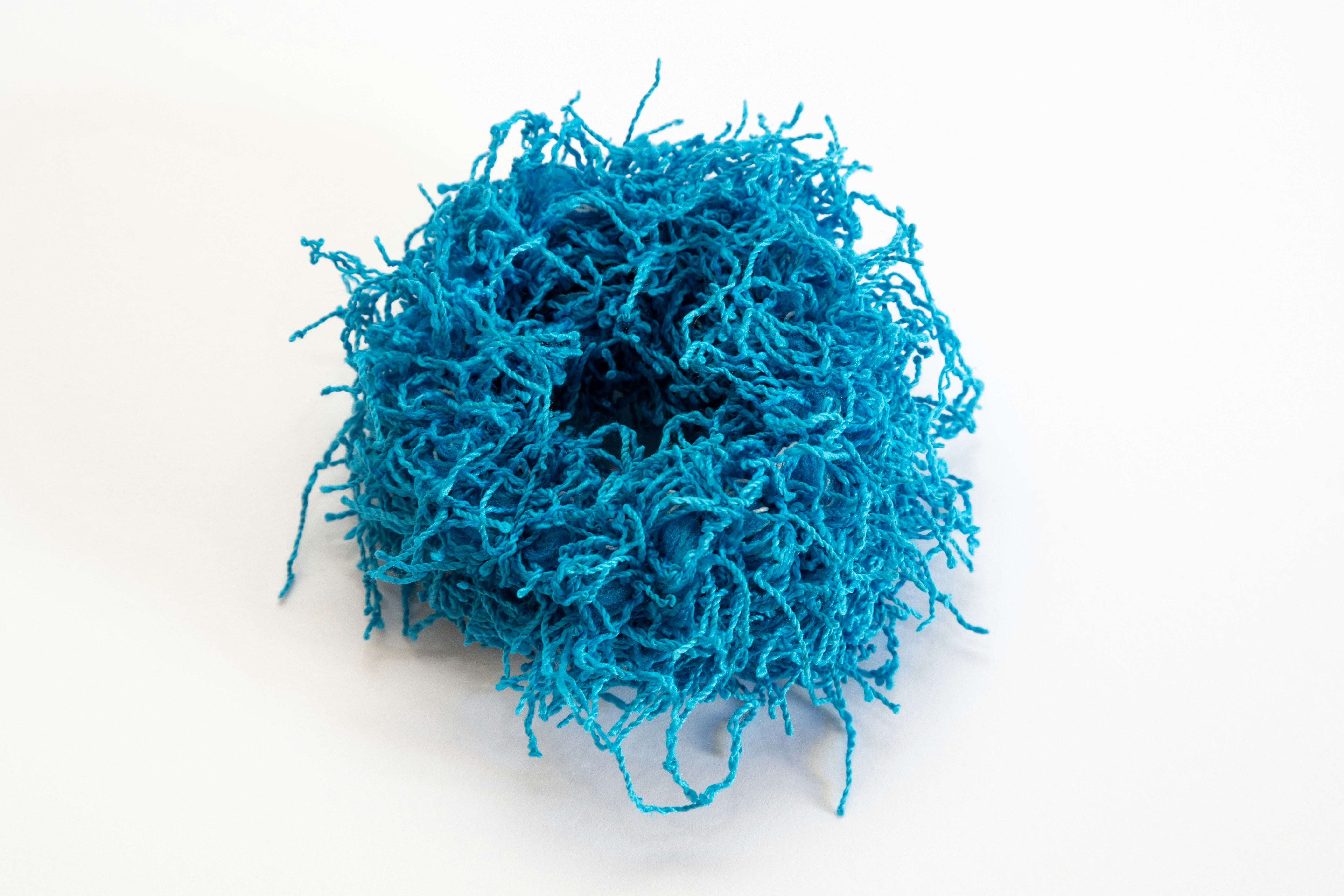 woman blue hair band on white background | a ball of blue yarn on a white surface