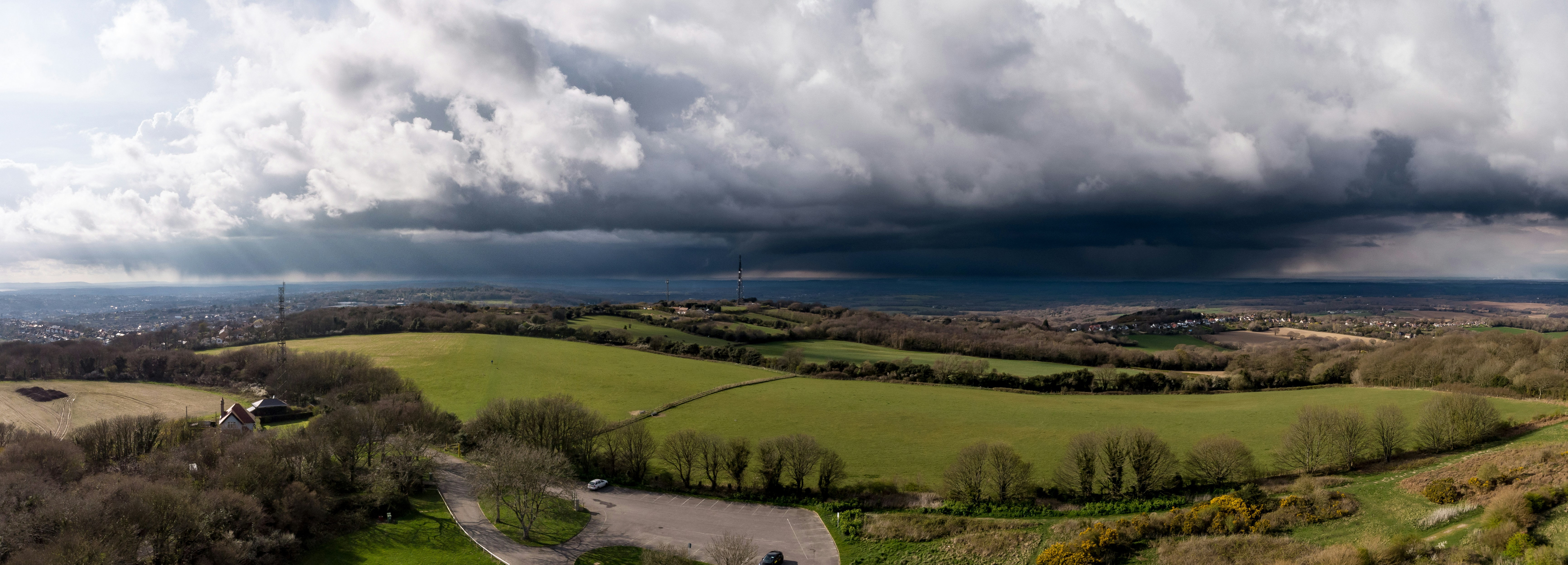 Panoramic view of a storm captured with a drone | an aerial view of a green field and a road