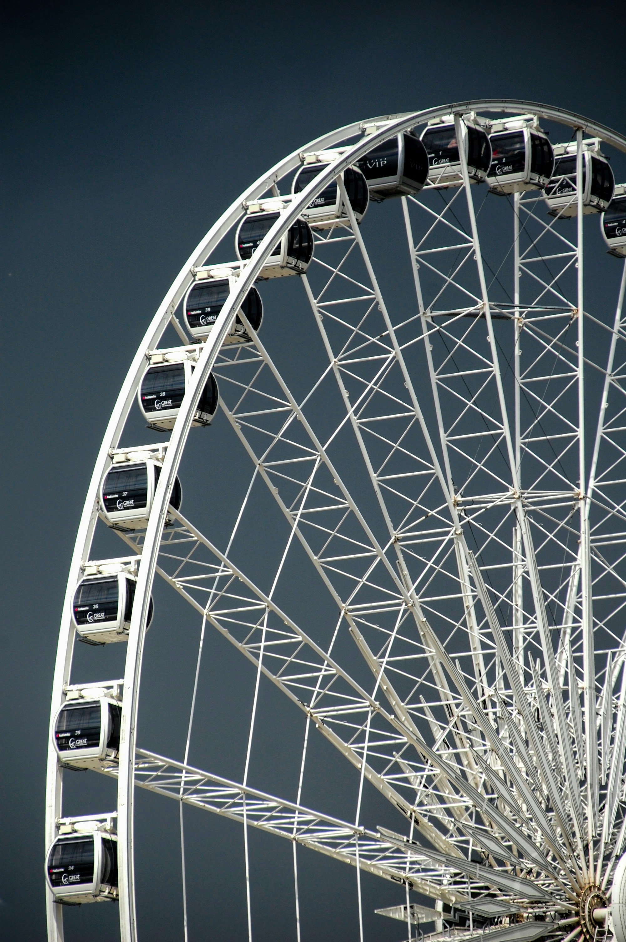 Close-up of a Ferris wheel showcasing its intricate structure and passenger cabins against a dark sky.