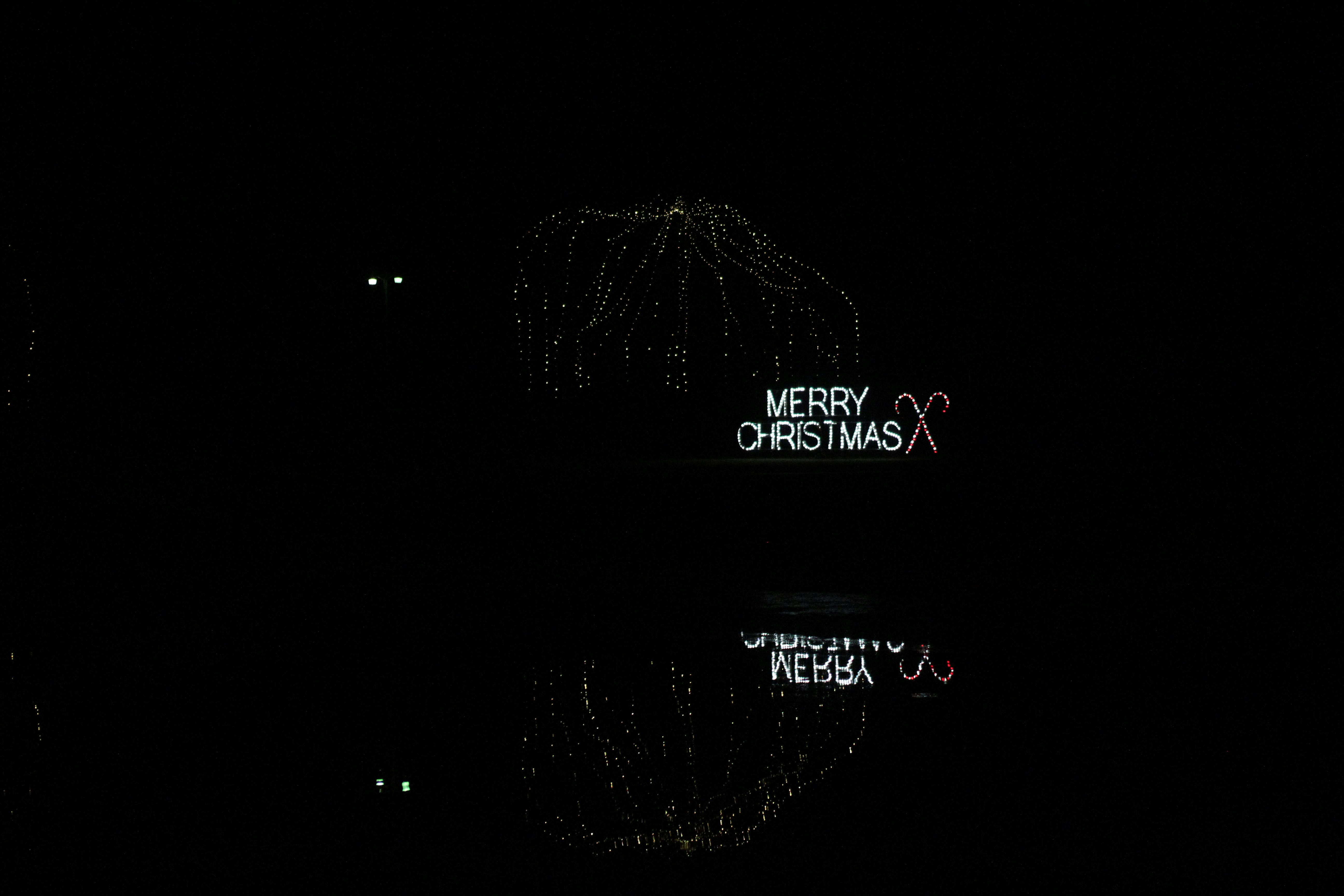 Echoes of Christmas Light: Sign Reflected on Quiet Water